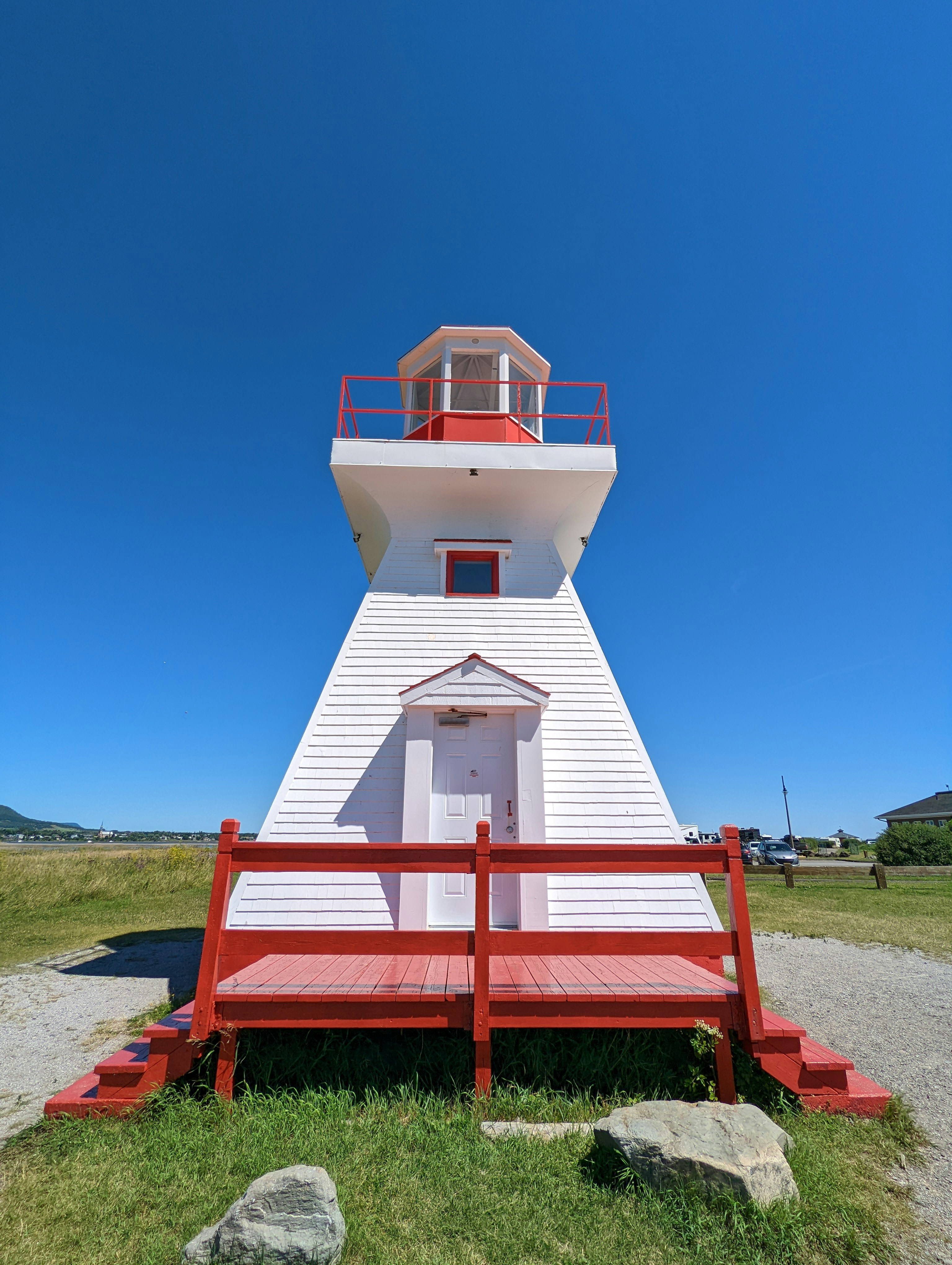 Crimson Railings Framing a White Beacon Under a Pristine Coastal Sky