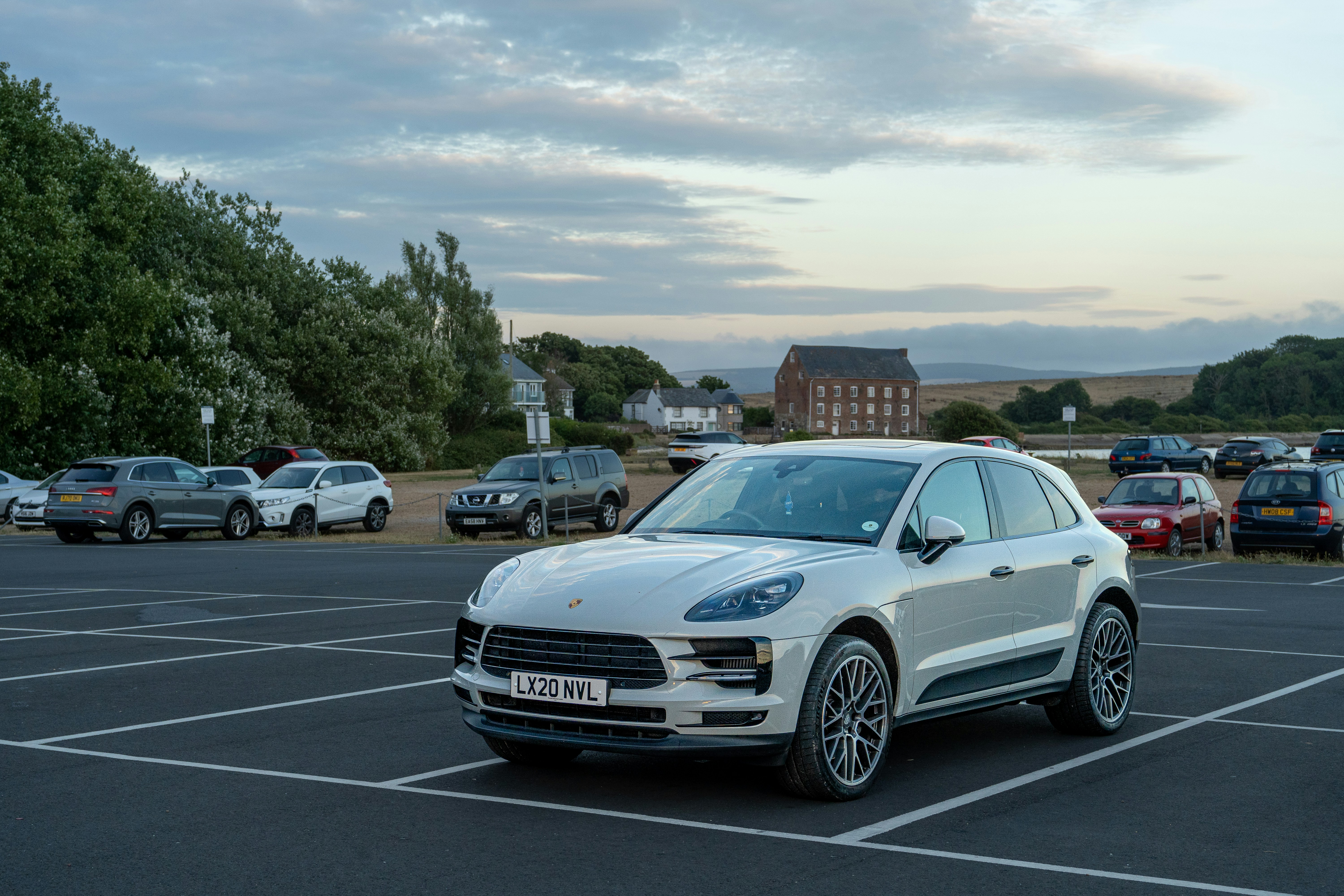 A Porsche in a car park. | a white car parked in a parking lot