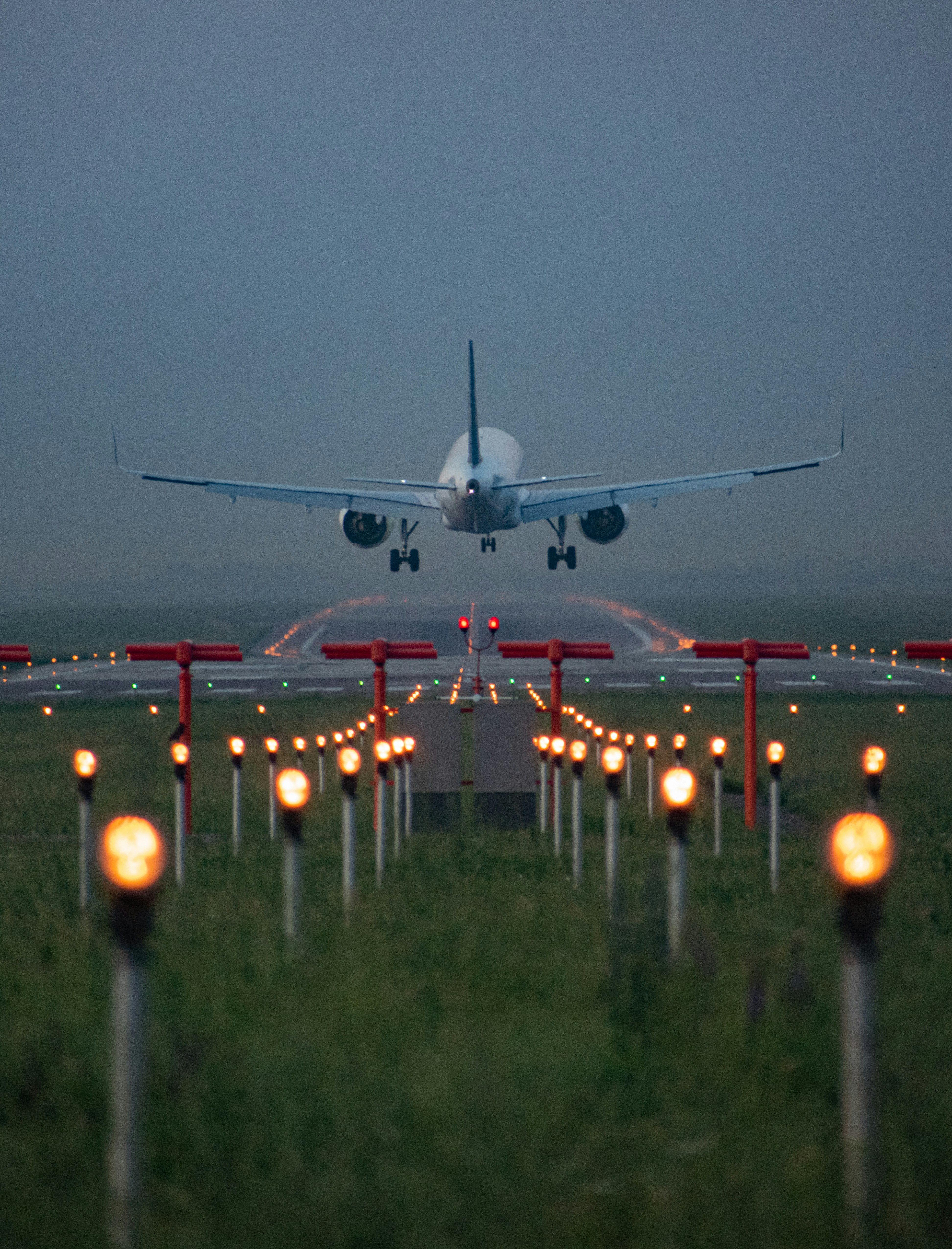Airplane descending onto a runway illuminated by guiding lights, set against a misty backdrop. The scene captures the essence of aviation precision.