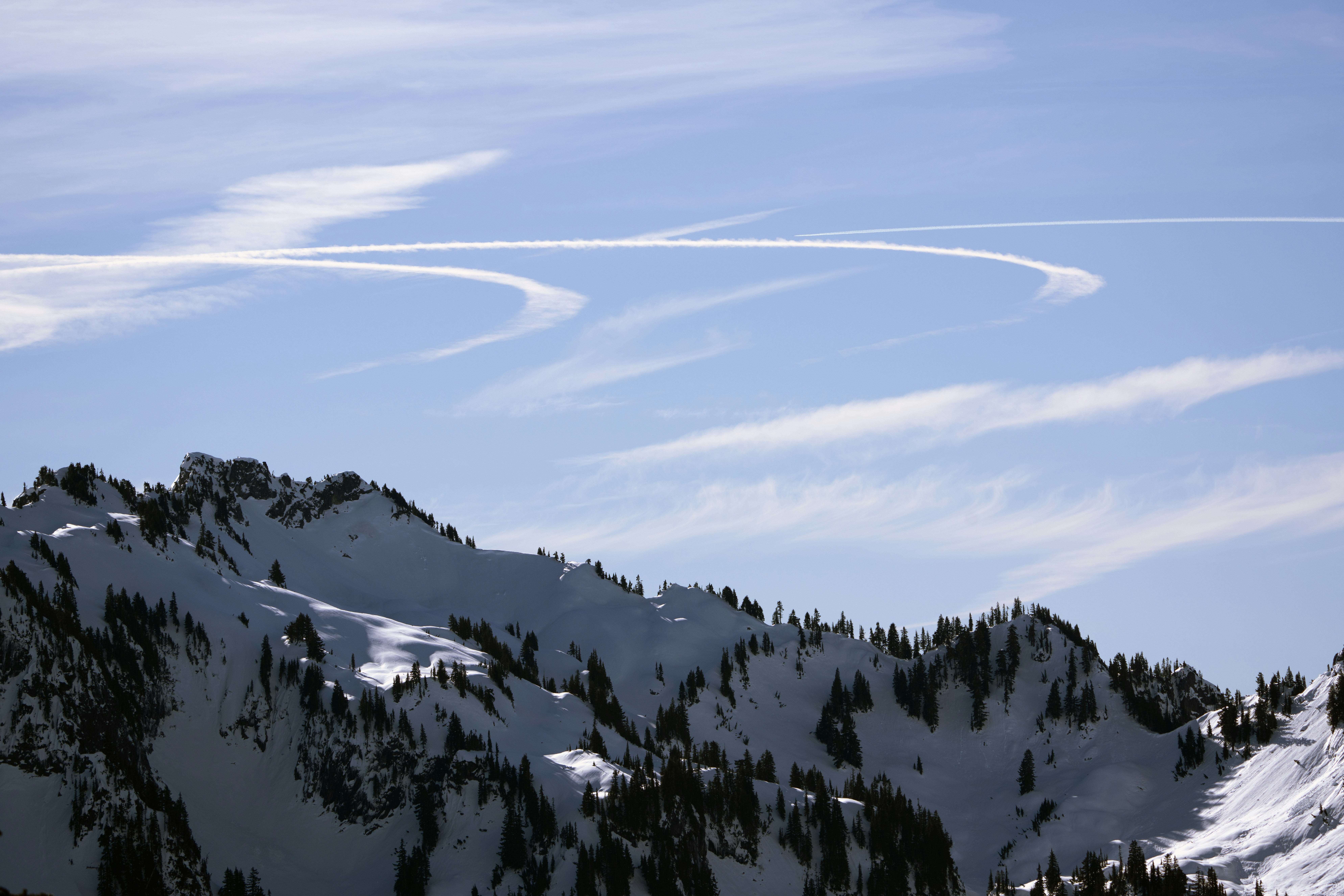 Snow-Crowned Peaks Under A Tracer-Sky