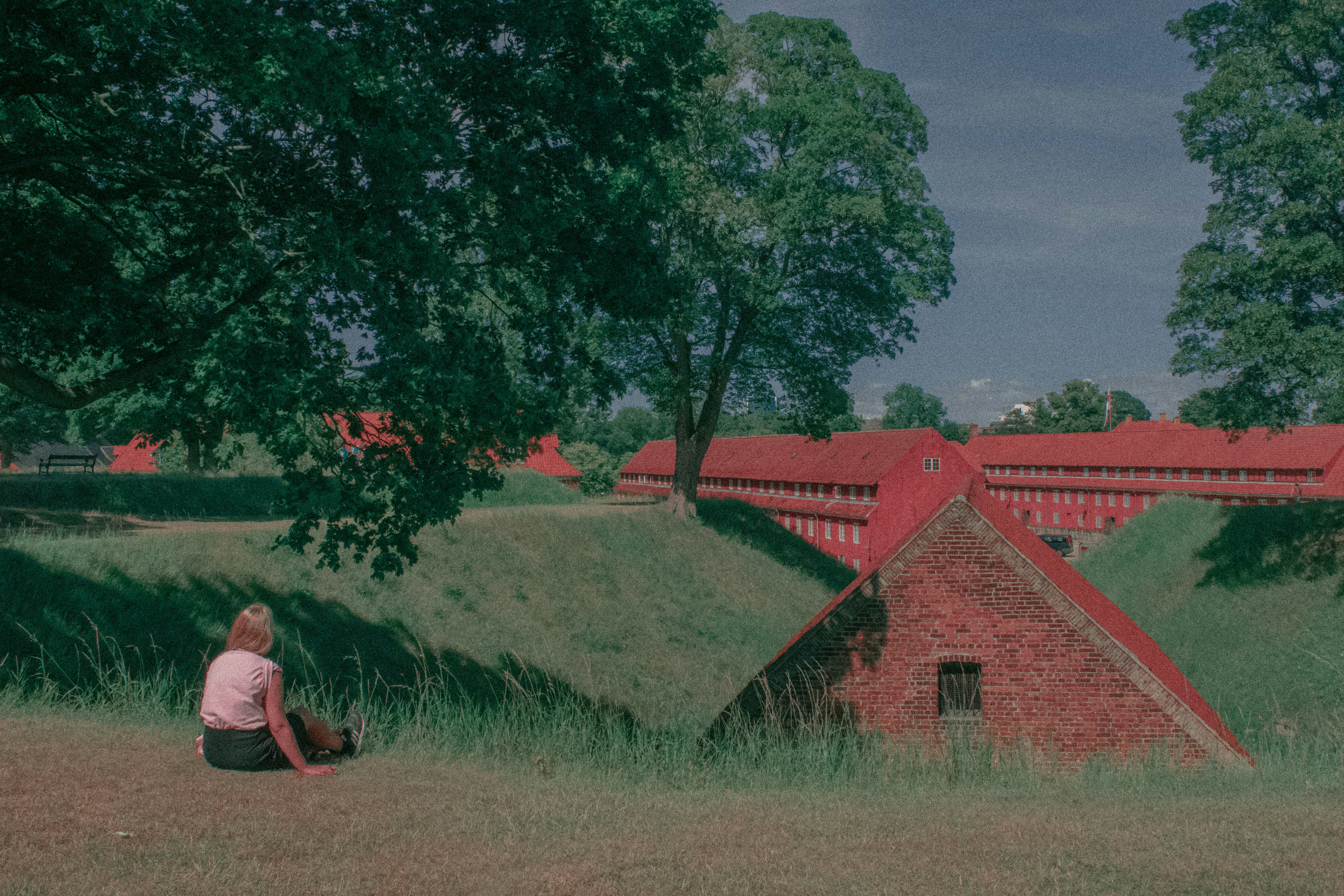  lone visitor at the red-roofed ruin under a canopy of trees