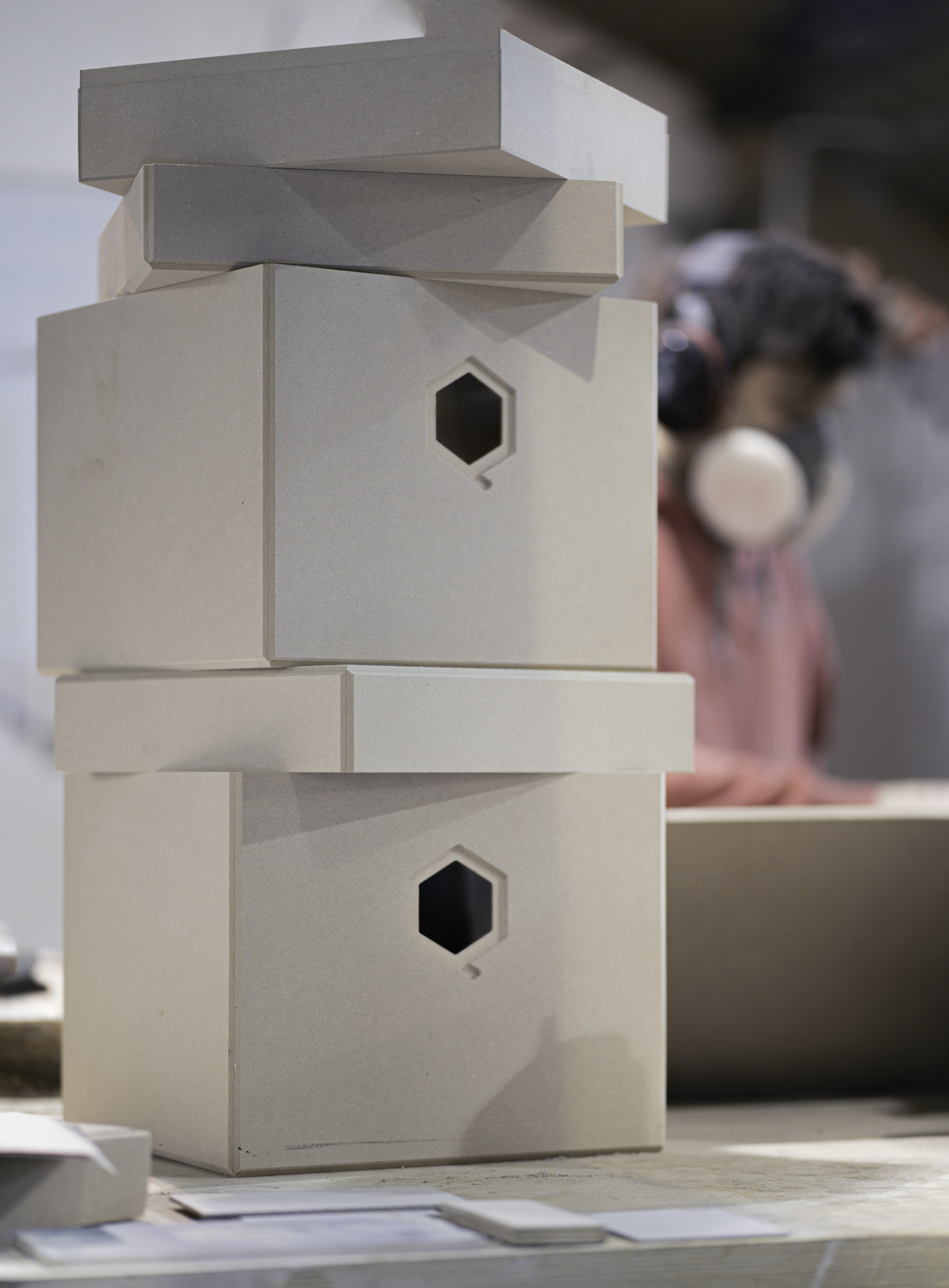 Stacked cardboard architecture with blurred observer in the background