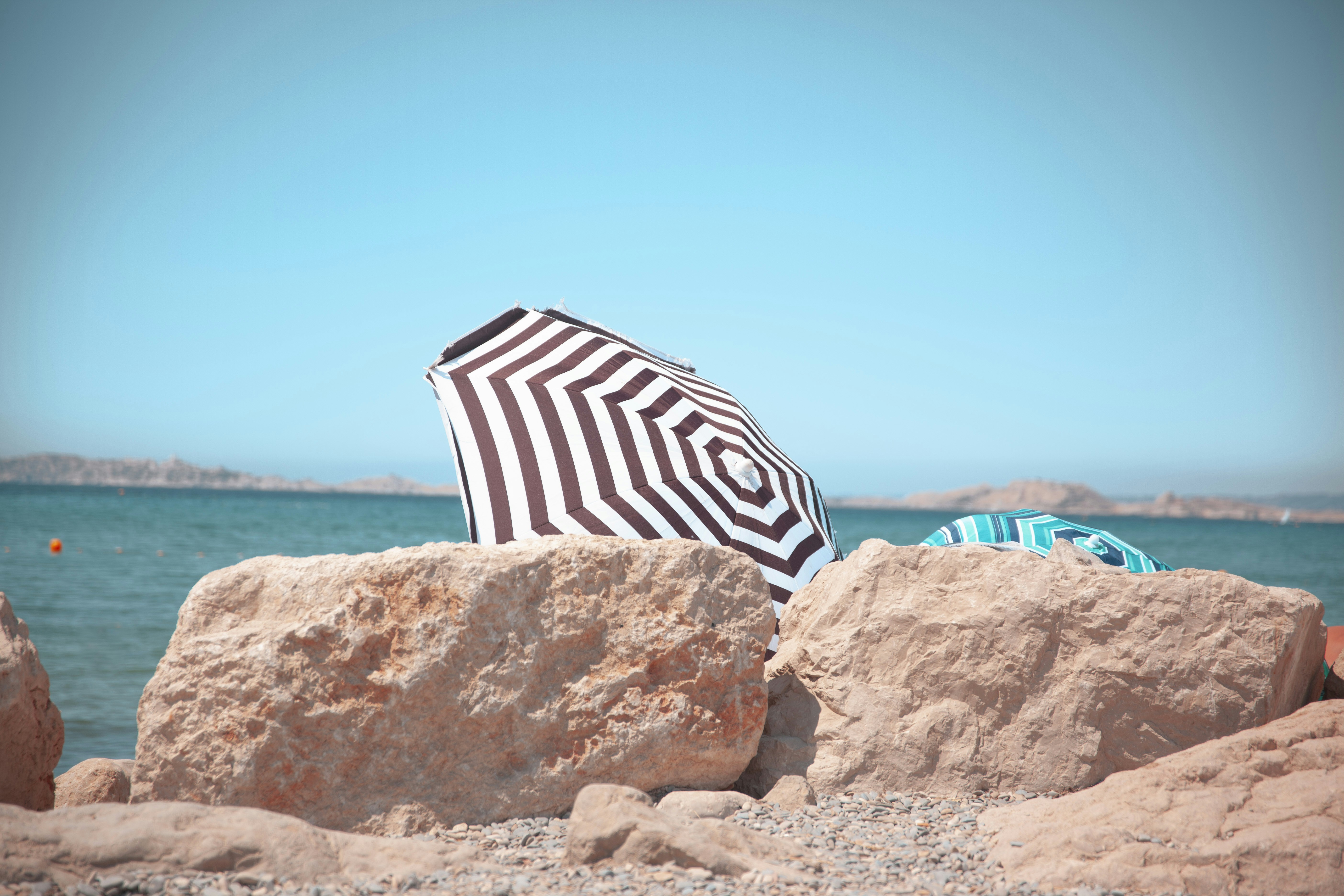 A striped striped object on rocks by water photo – Free Marseille Image ...