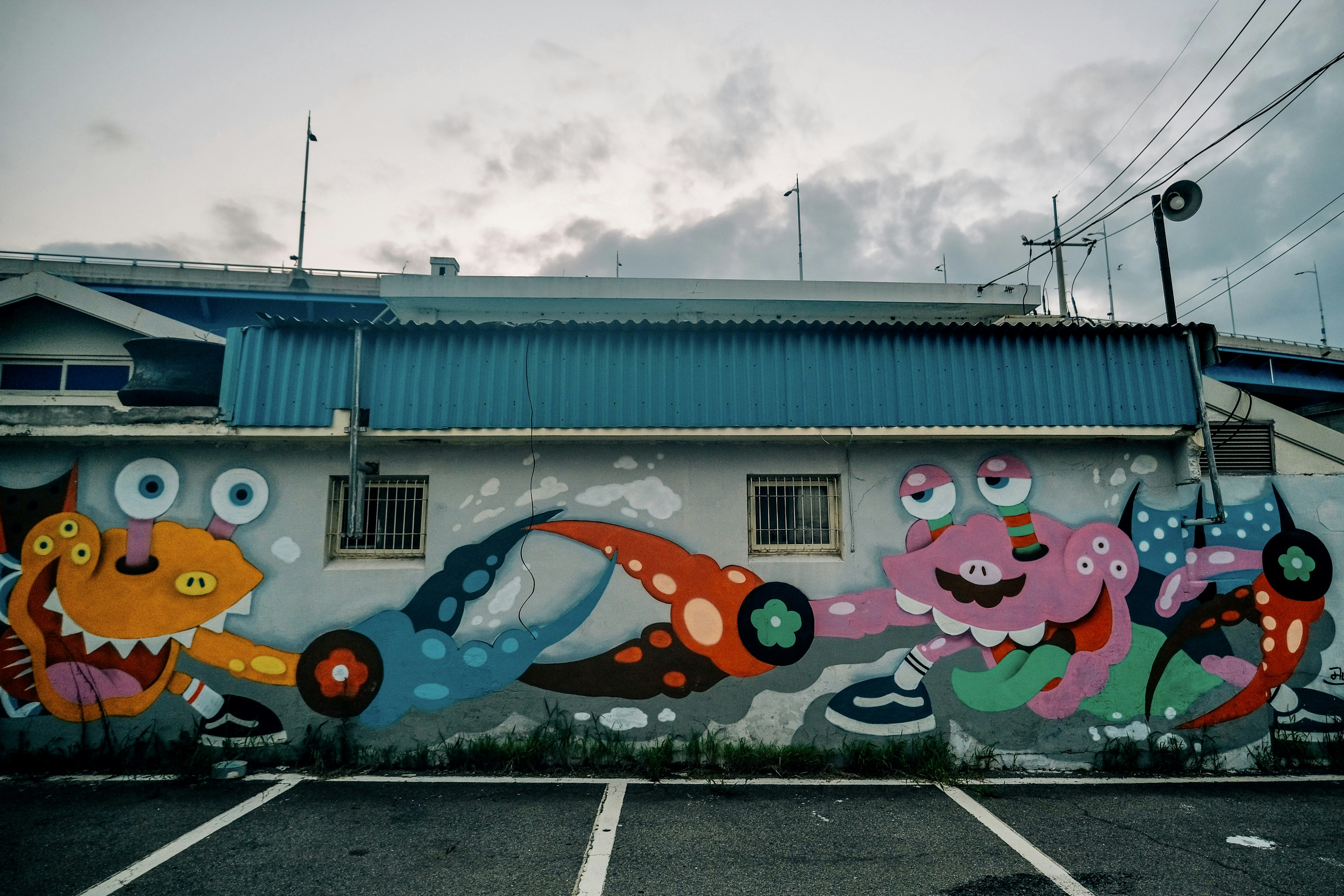 Colorful Alley Mural: A Parade of Playful Monsters Across a Blue Wall