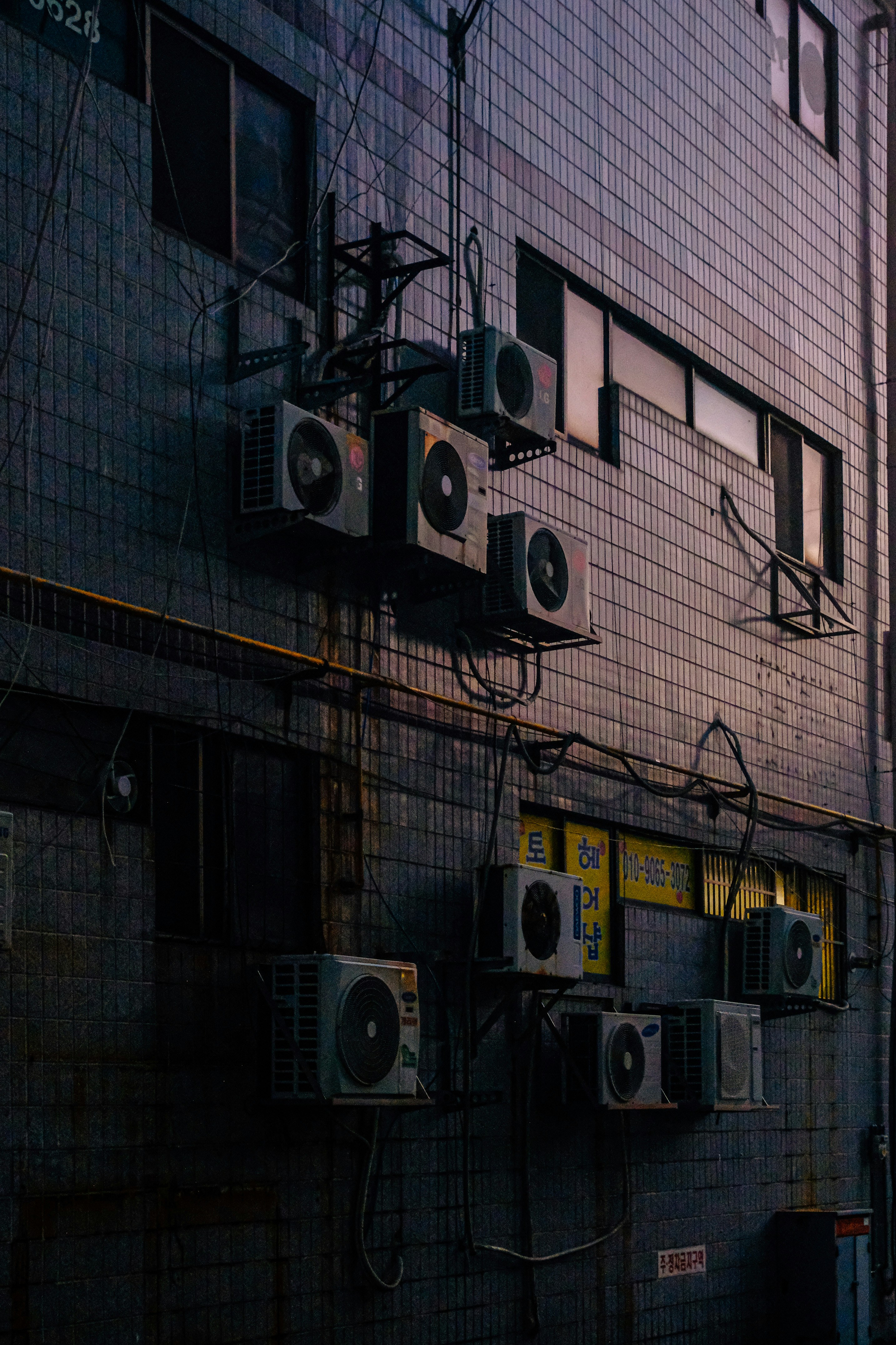 Nocturnal Mosaic: A Wall of Air-Conditioning Units and Wiring