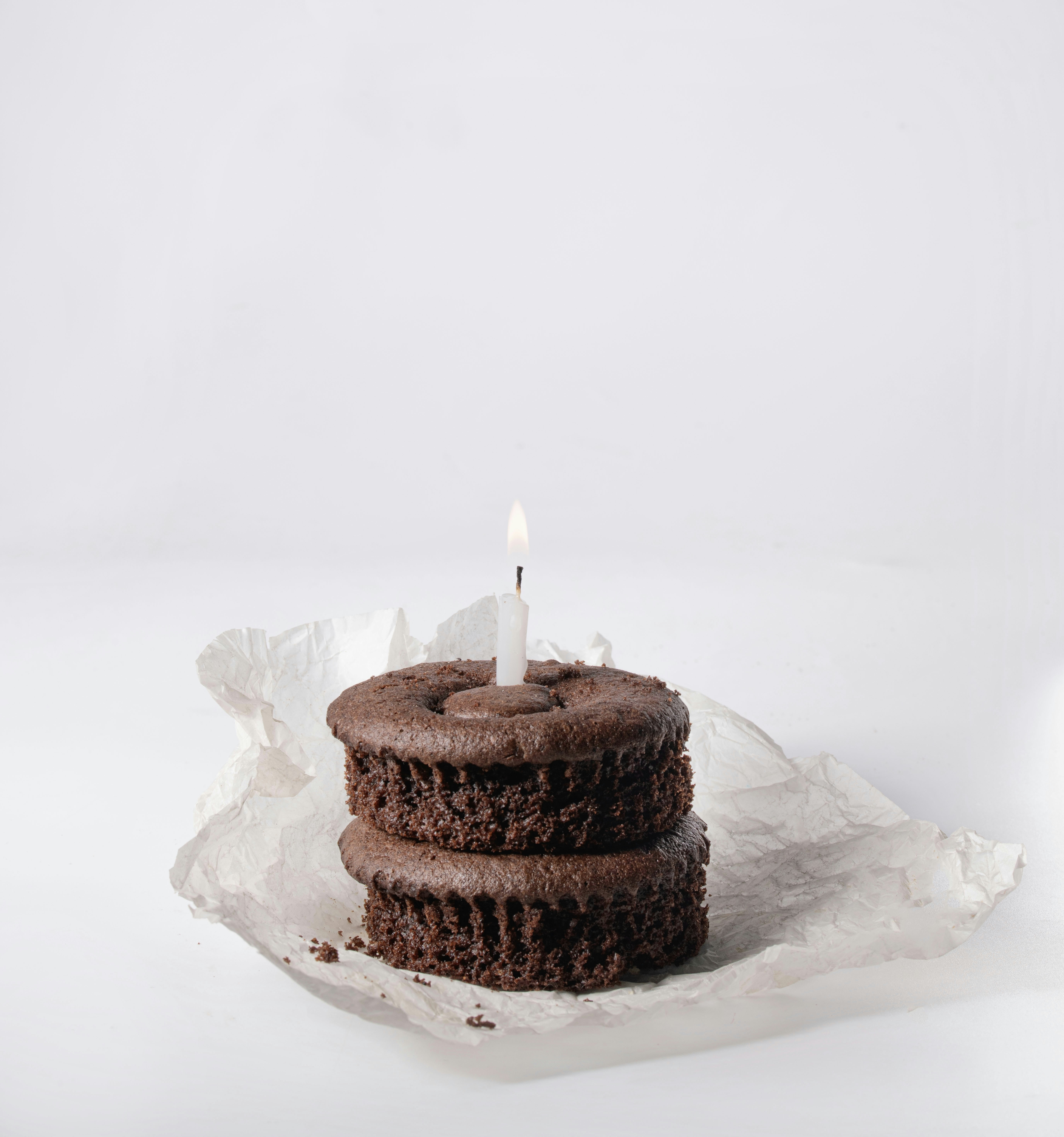Candle atop a Two-Layer Chocolate Cake on Crumpled Parchment