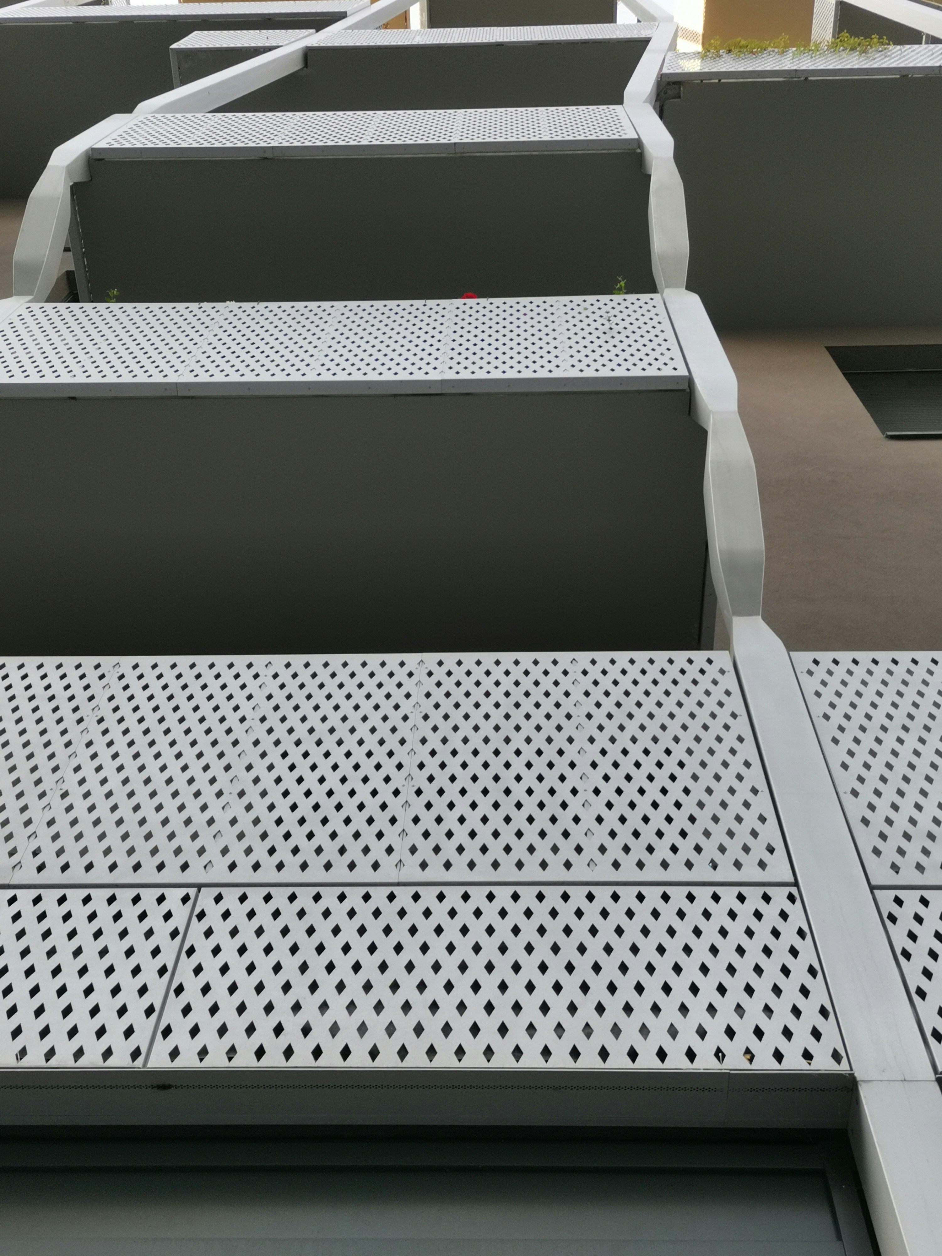 A close-up view of modern architectural balconies showcasing intricate patterns and clean lines. The design emphasizes symmetry and contemporary aesthetics.