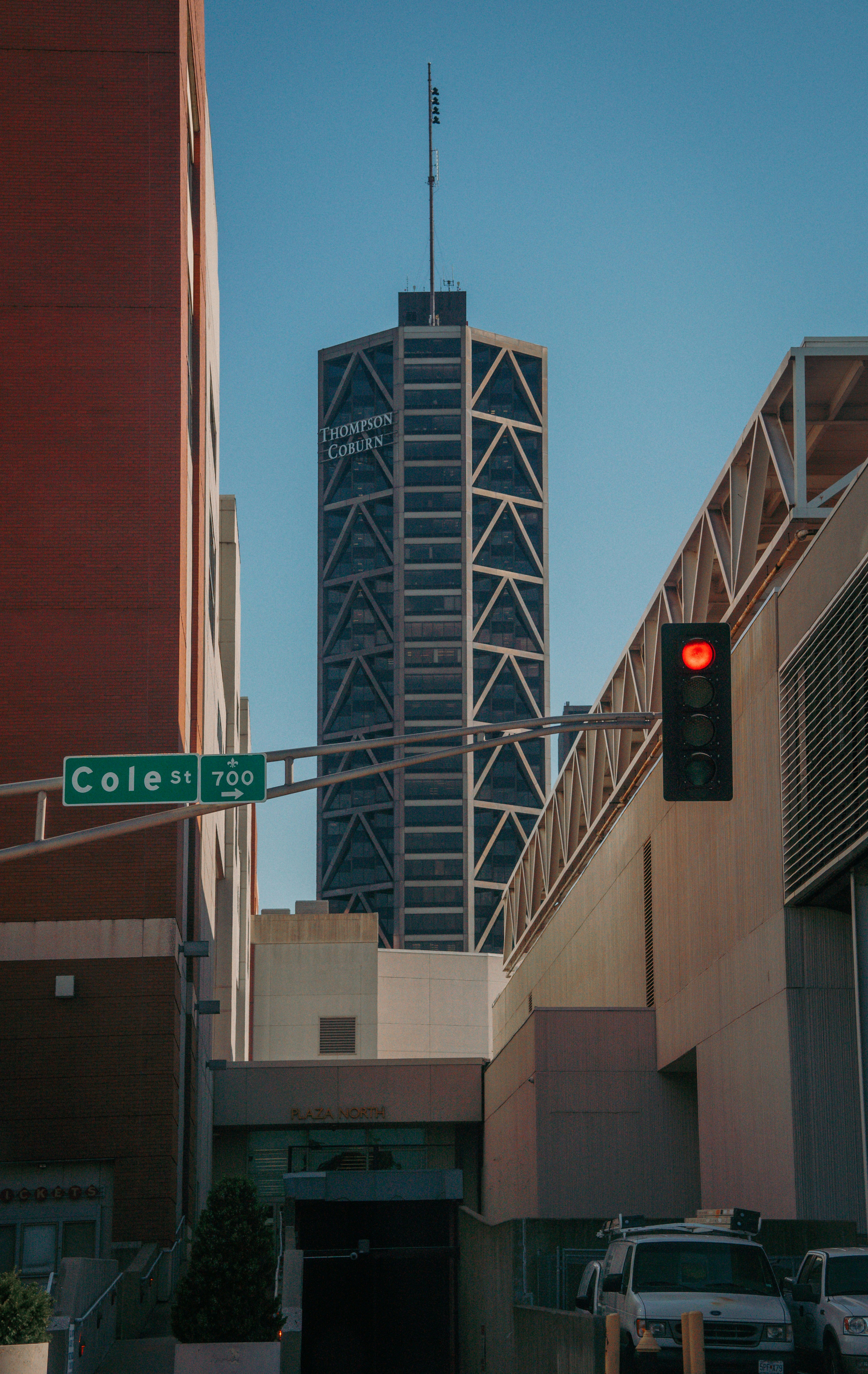 The Thompson Coburn building rises prominently amidst urban structures, framed by a traffic light and street sign. The scene captures the essence of city life.