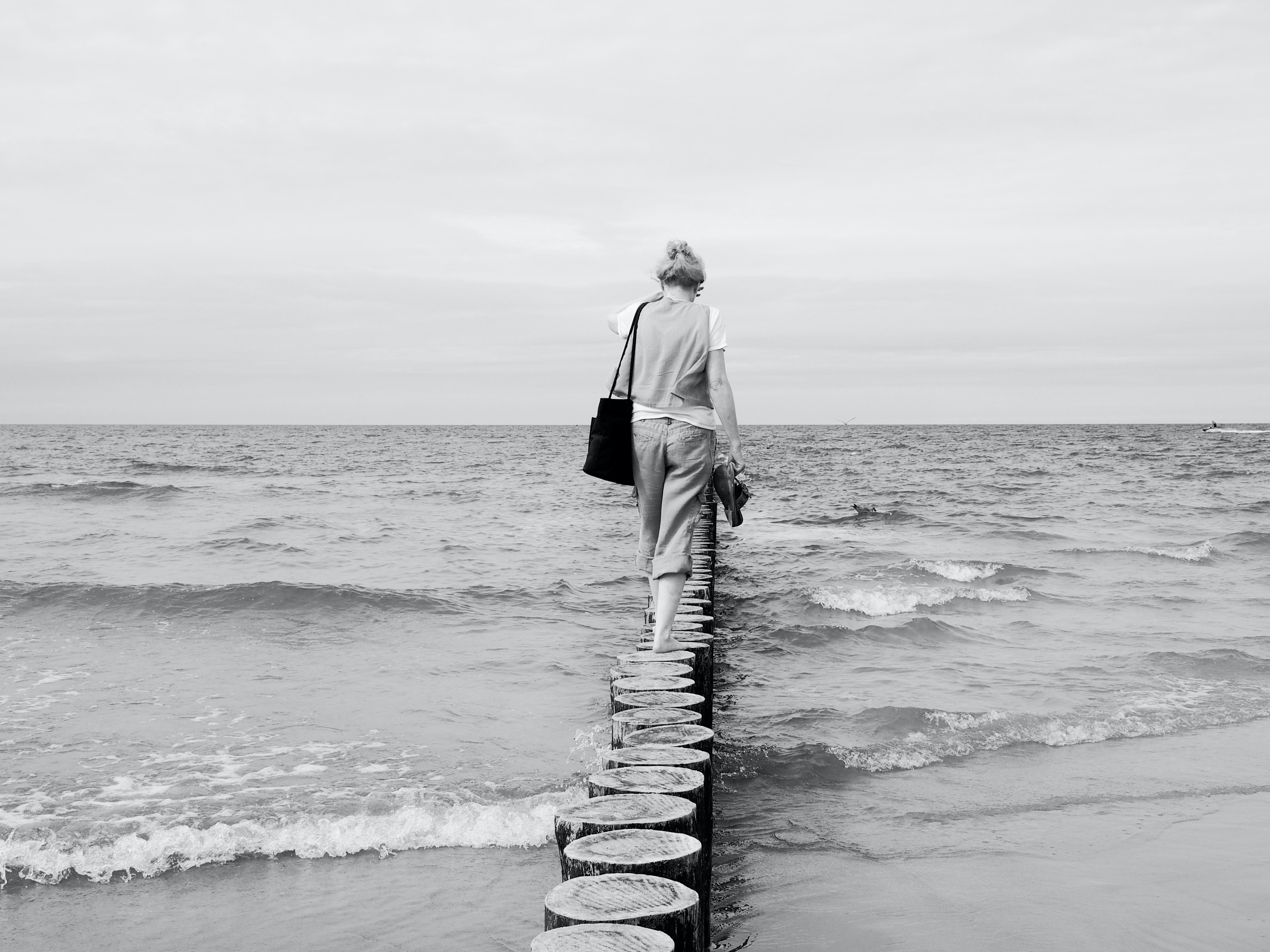 A man walking on a stone path by the ocean photo – Free Beach Image on ...