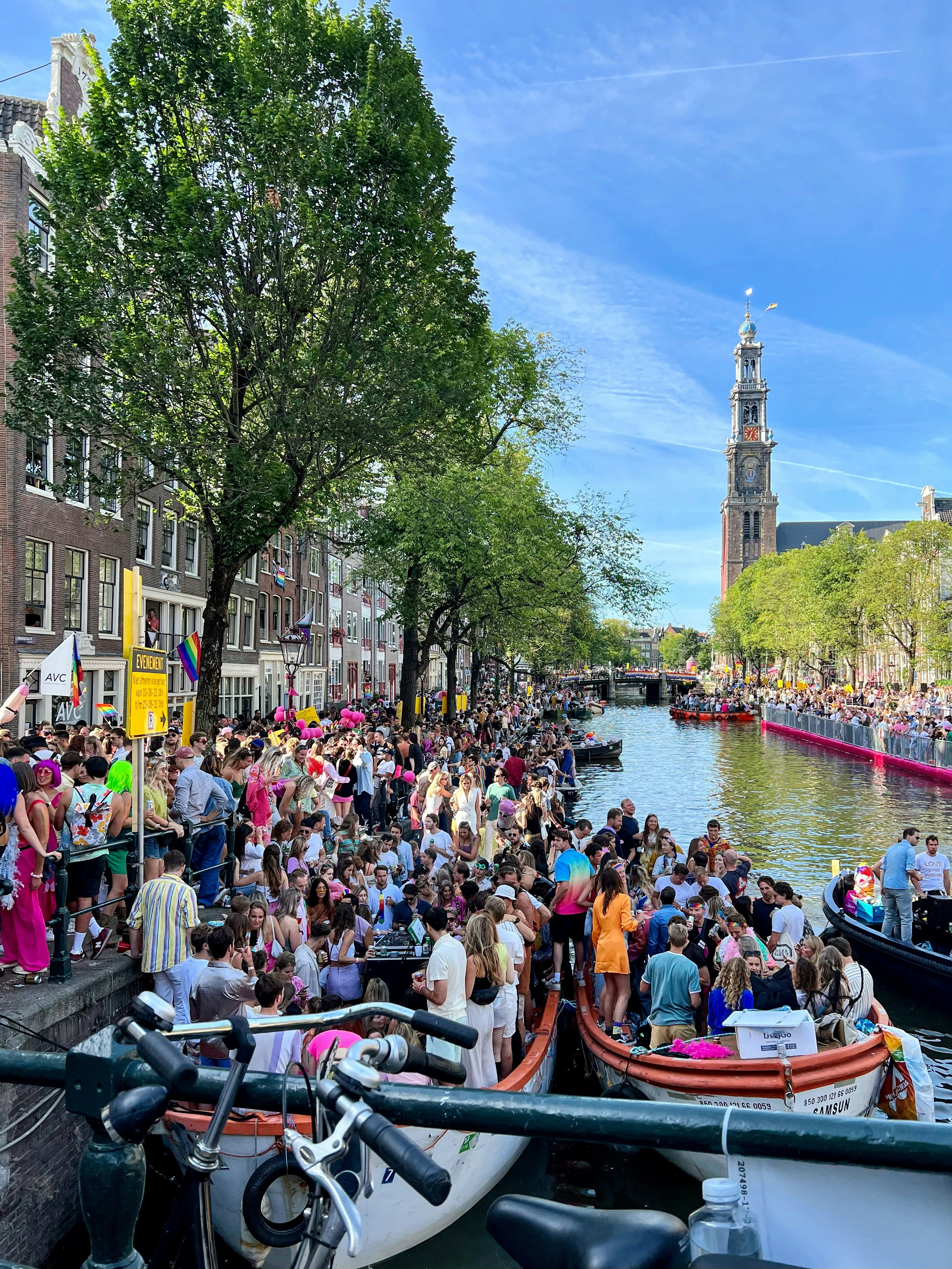 Sunlit Canal Carnival: Boats, Bystanders, and a Historic Clock Tower
