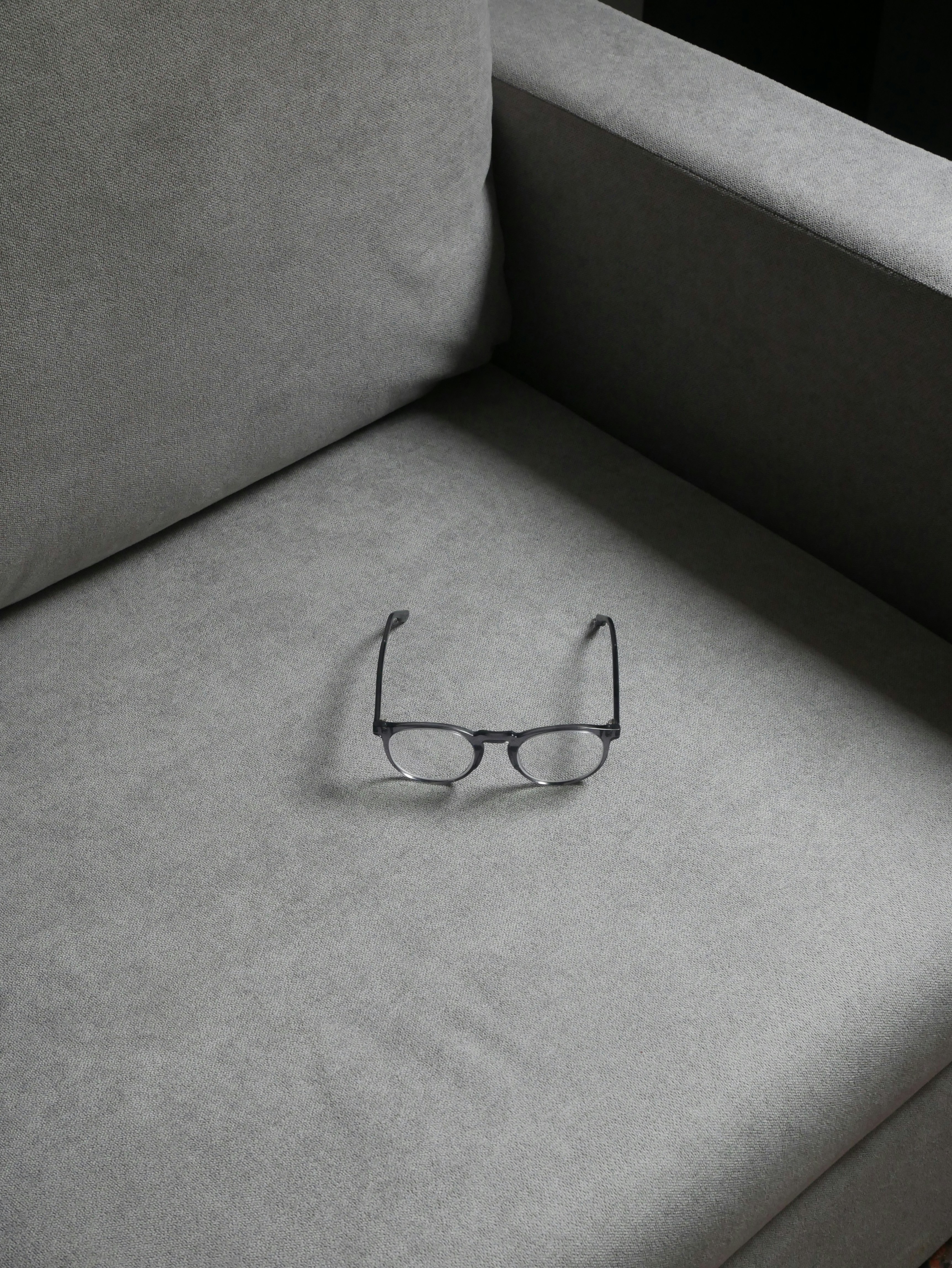 A pair of glasses resting on a gray sofa, symbolizing a moment of pause and reflection.