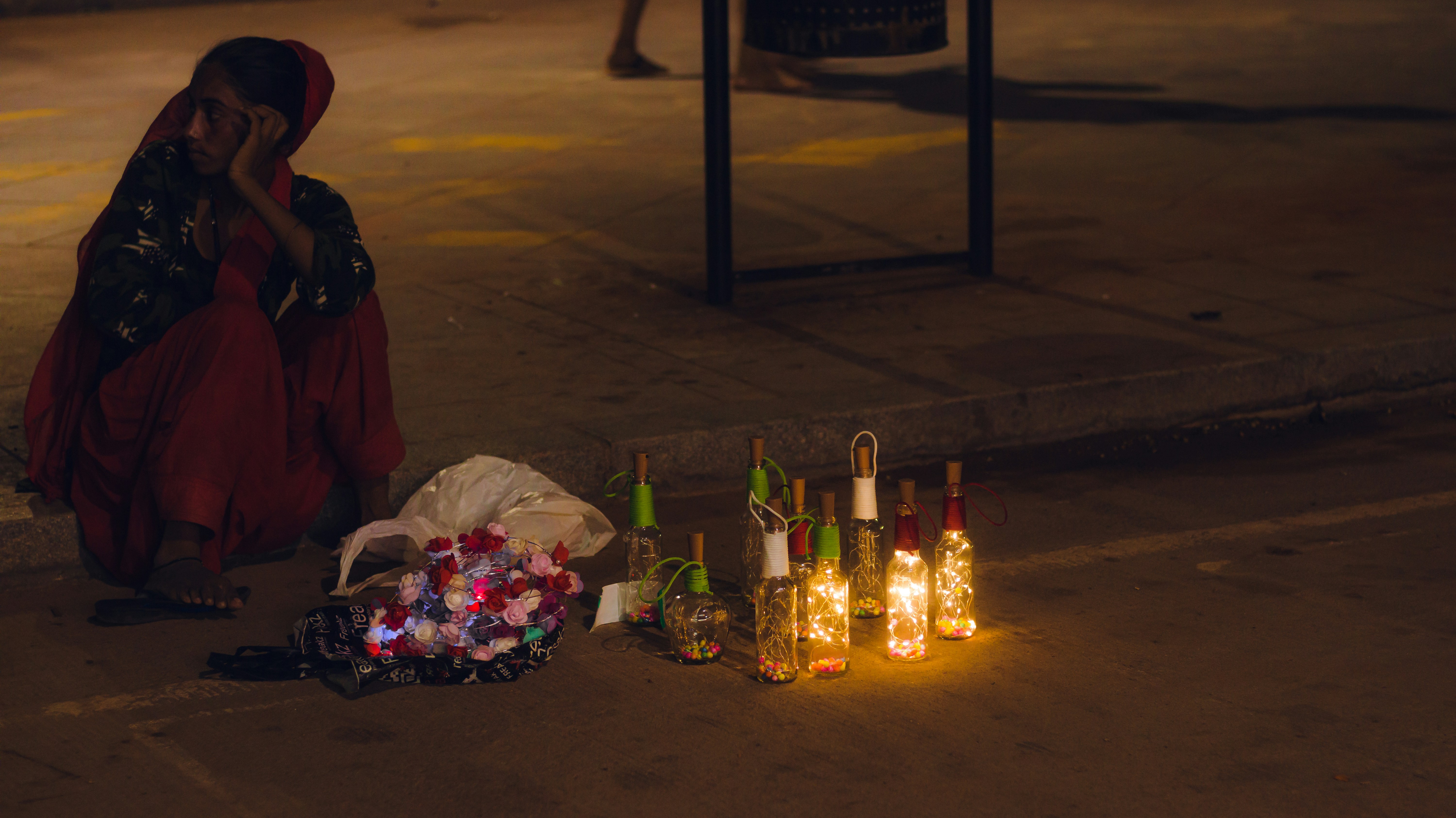 Lone Shrine of Light: Bottles and Bouquet Beneath Streetlamp