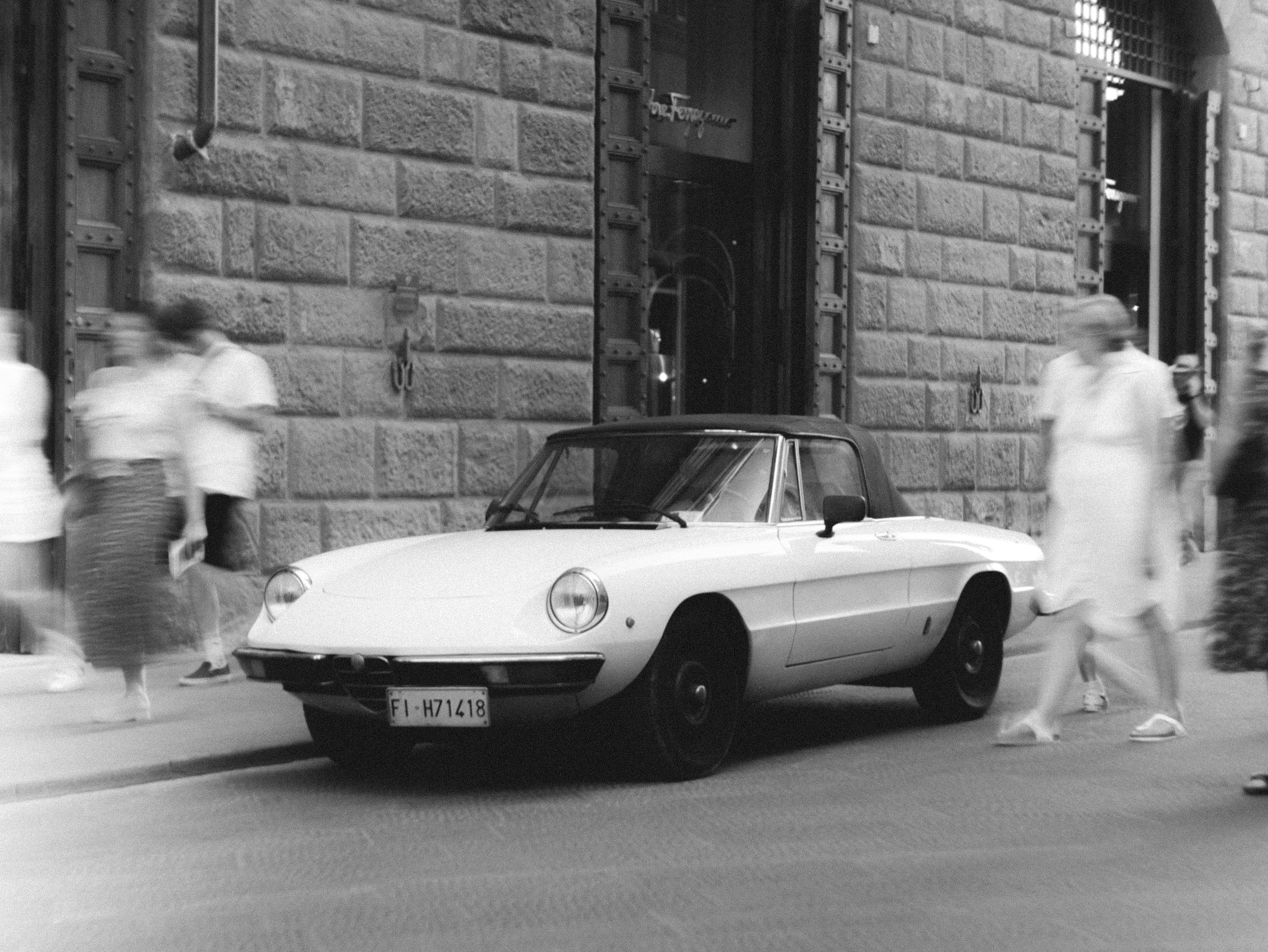 A White Mid‑Century Sports Car Holds Ground as Pedestrians Blur By