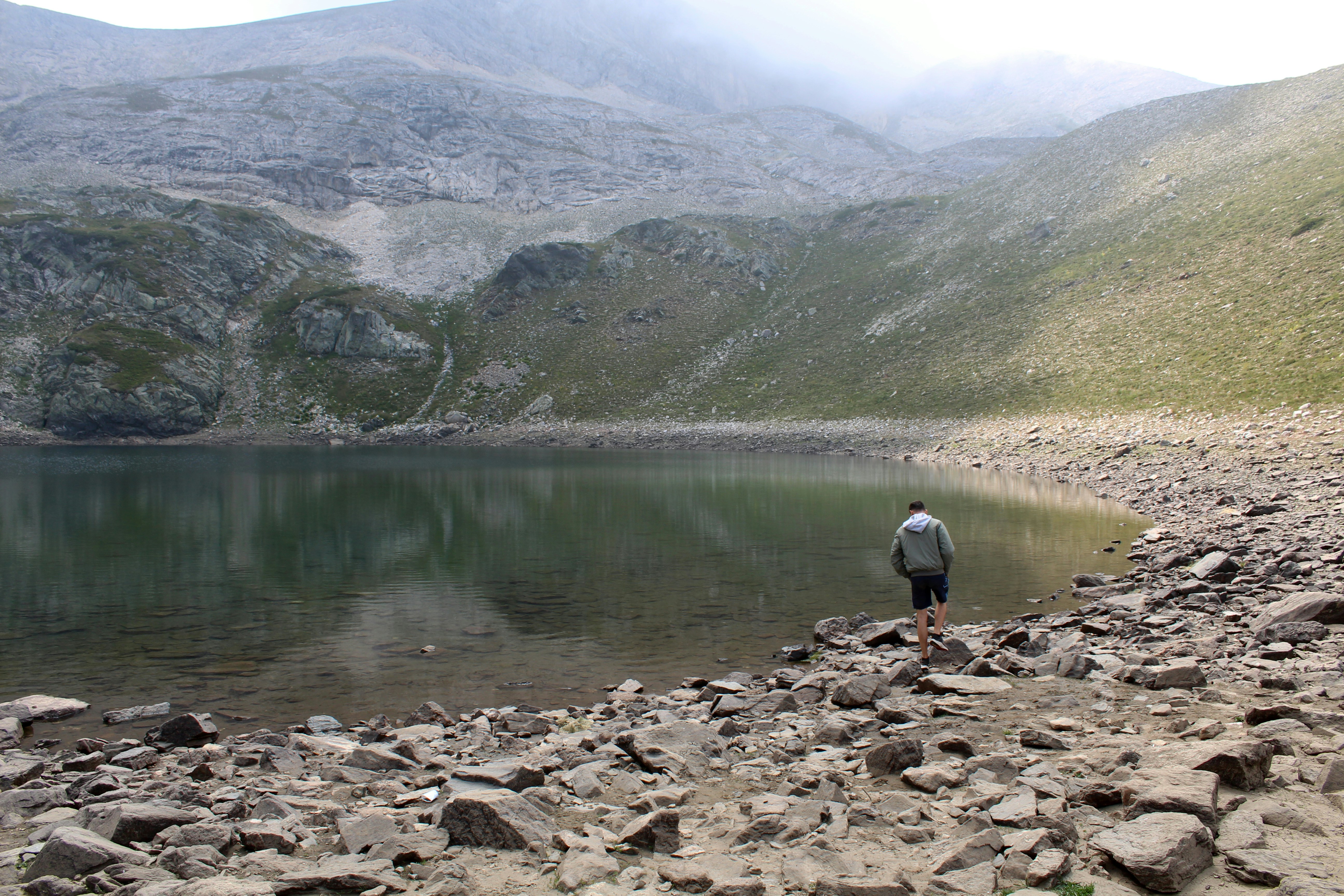 Un homme debout sur une rive rocheuse au bord d’un lac photo – Photo ...