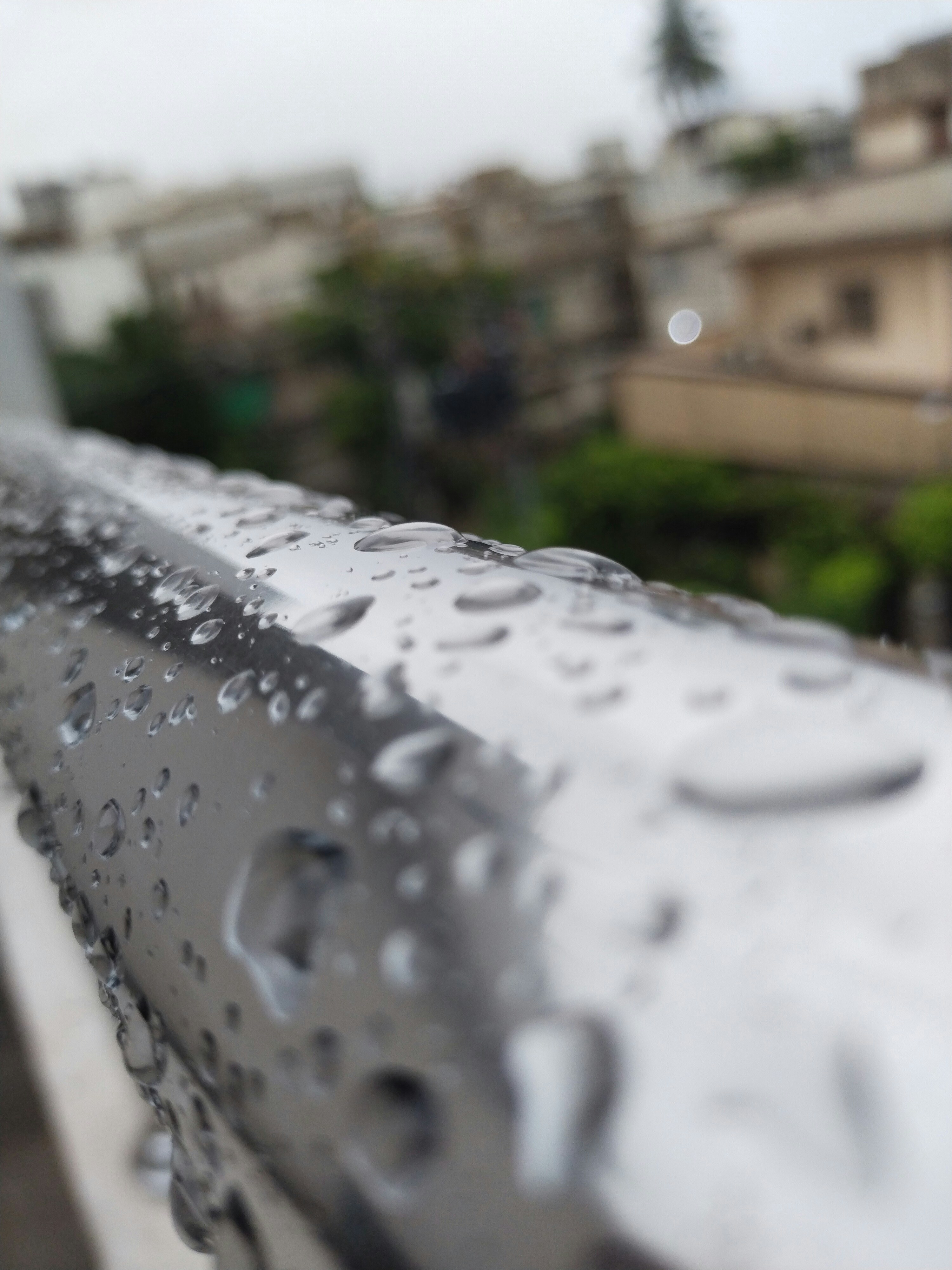 Rain-Kissed Rail: Droplets in Focus, City Blur Beyond