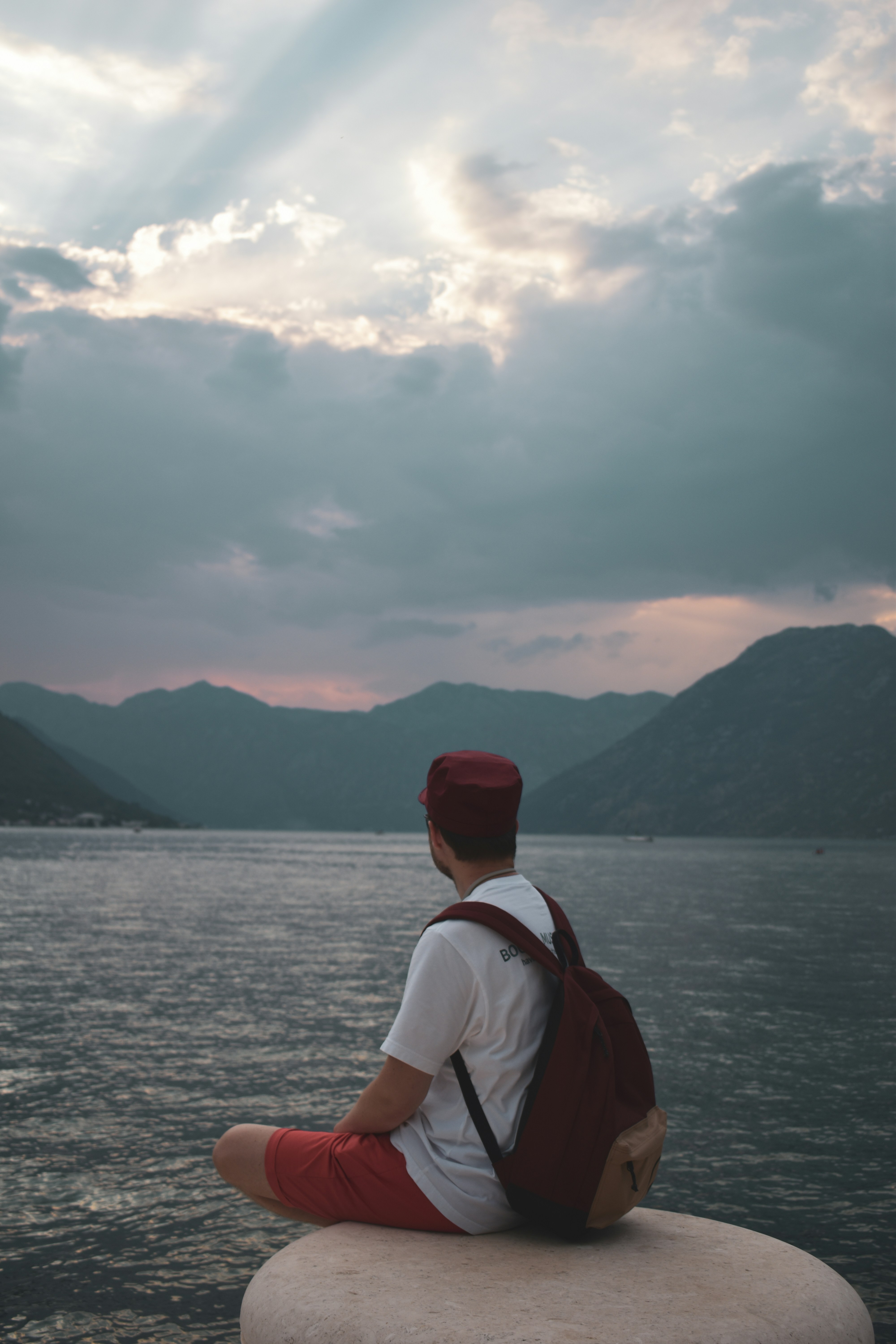 Dusk by the Quiet Lake: A Seated Wanderer with a Red Backpack