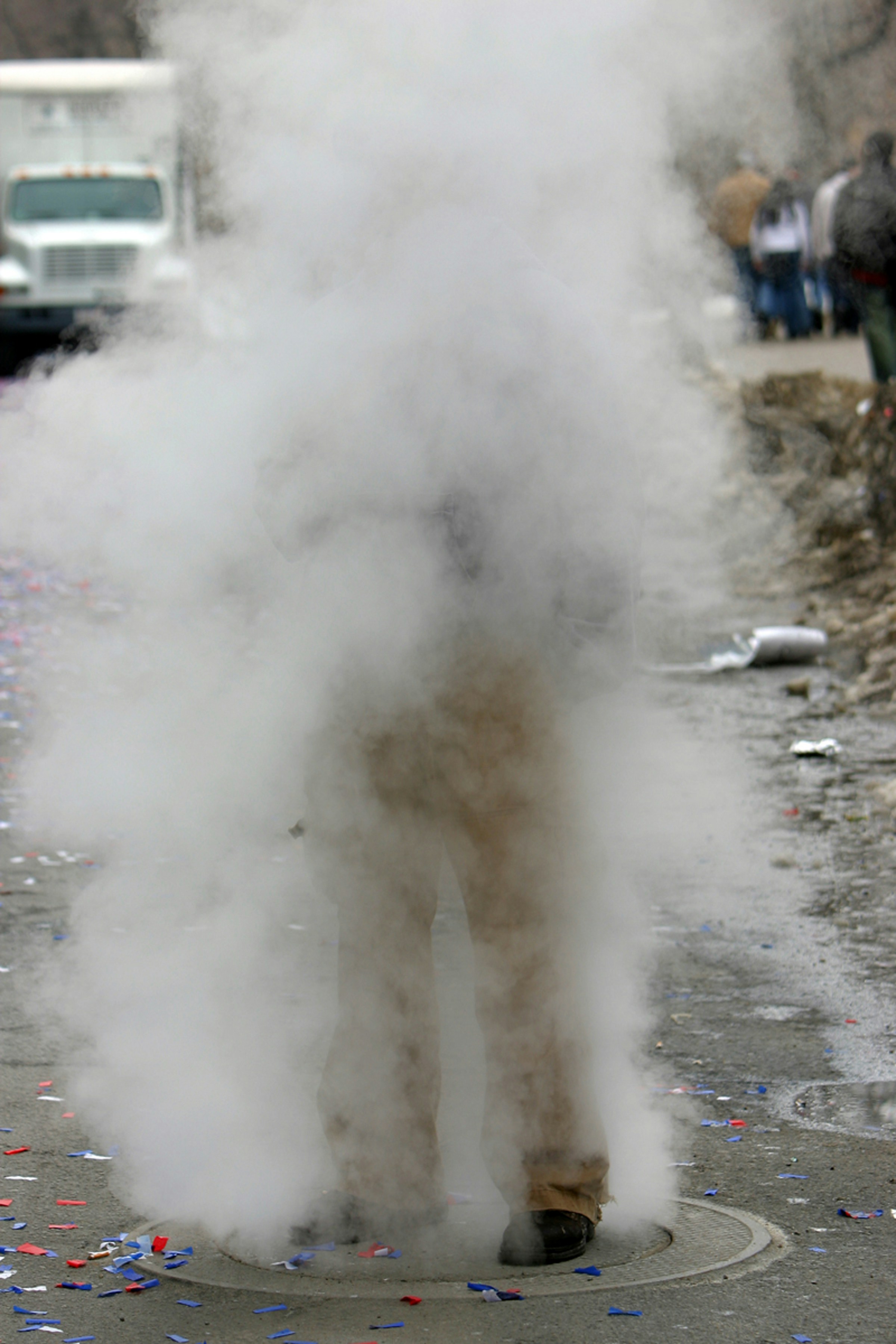 Fog of Protest: Steam Rising from a Manhole as Onlookers Fade in the Distance