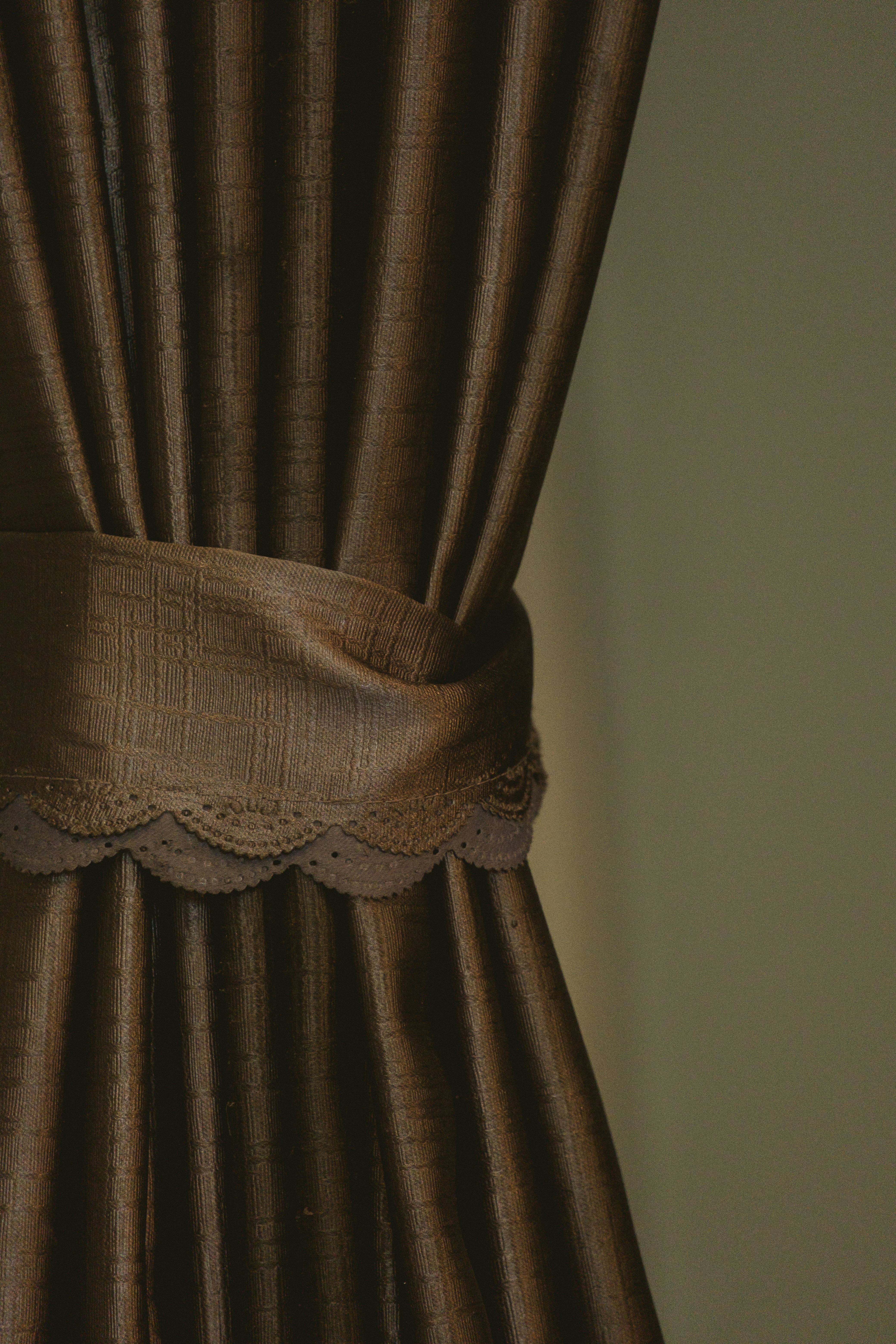 Curtained Elegance: A Quiet Moment with Ornate Tie and Shadowed Fabric