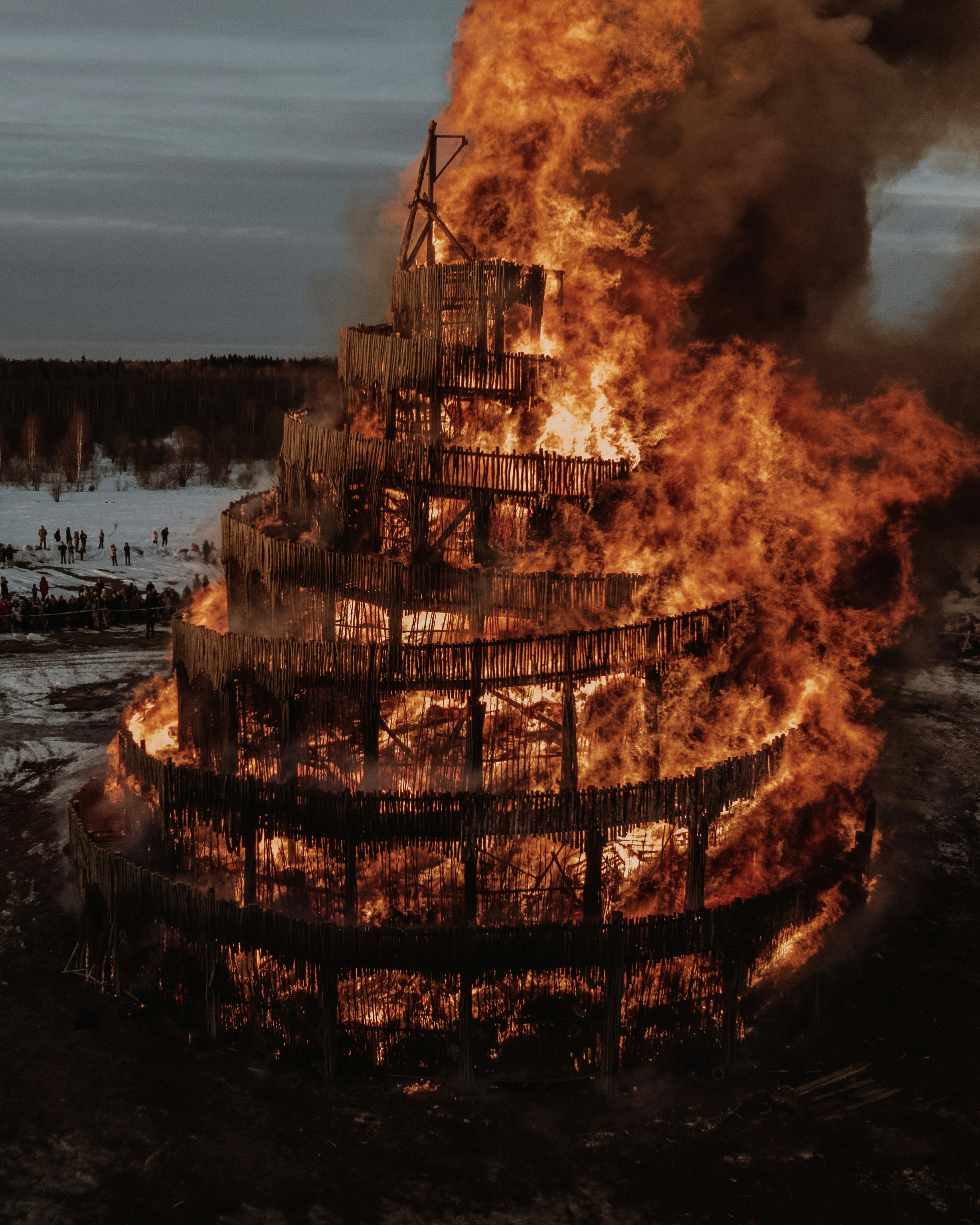 Spiral Inferno over the Ice: A towering bonfire spirals skyward on a frozen lakeshore