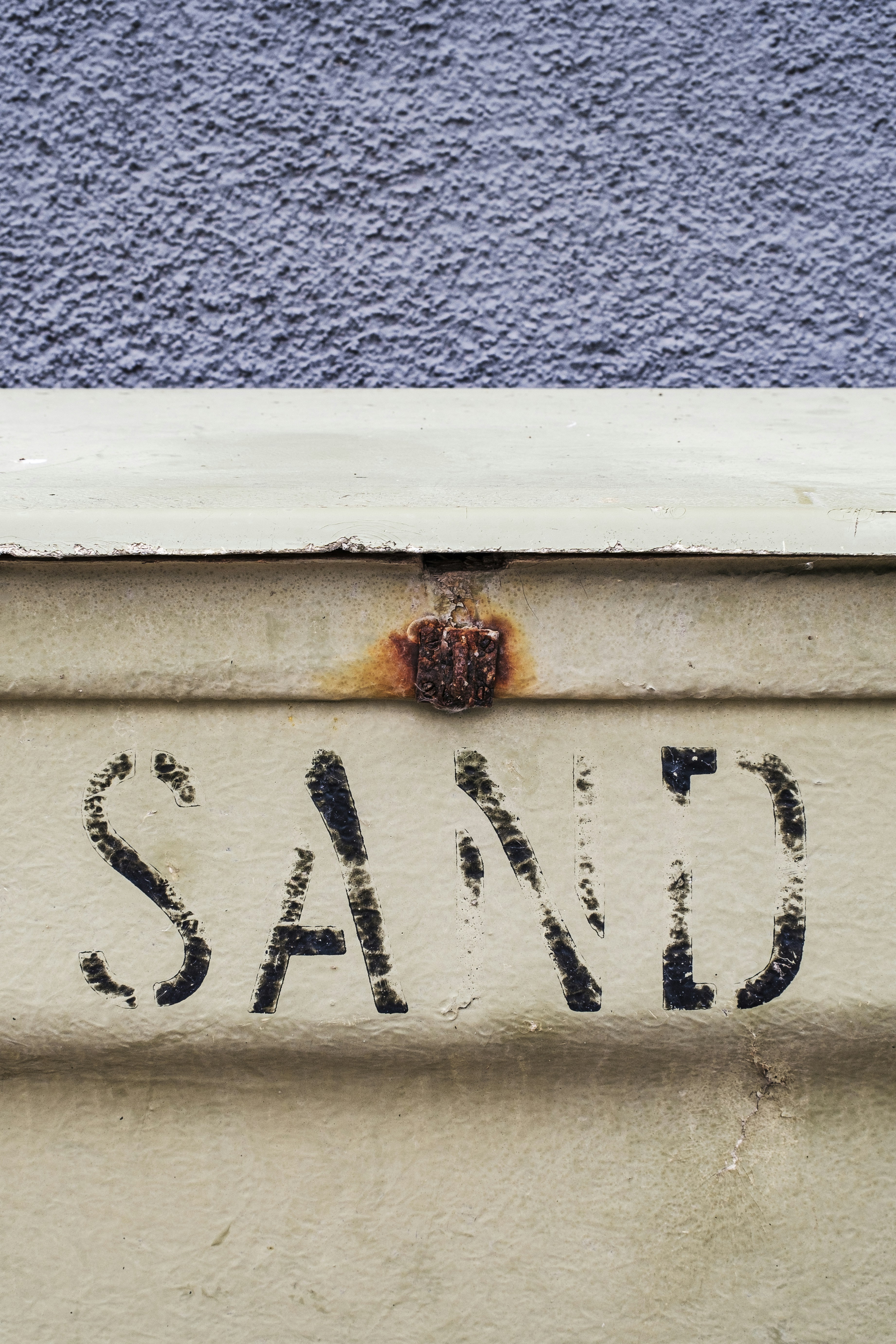 Rust in the Sandlight: A Close-Up of a Weathered Bolt on a Faded Facade