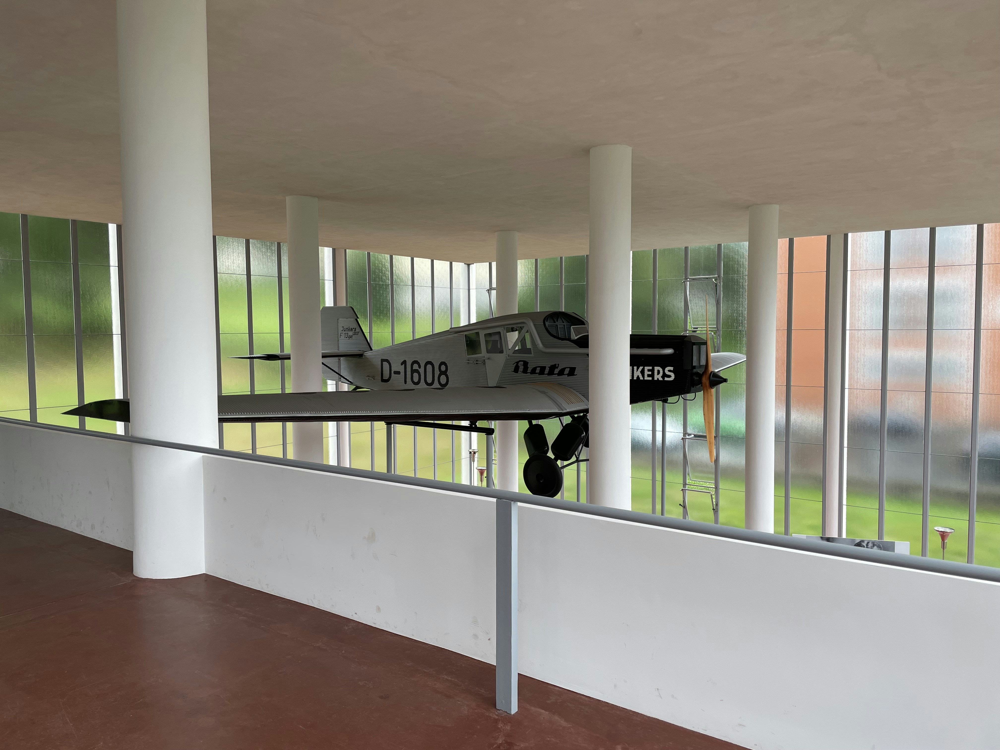 Vintage aircraft displayed within a modern architectural space, showcasing its design against a backdrop of natural light.