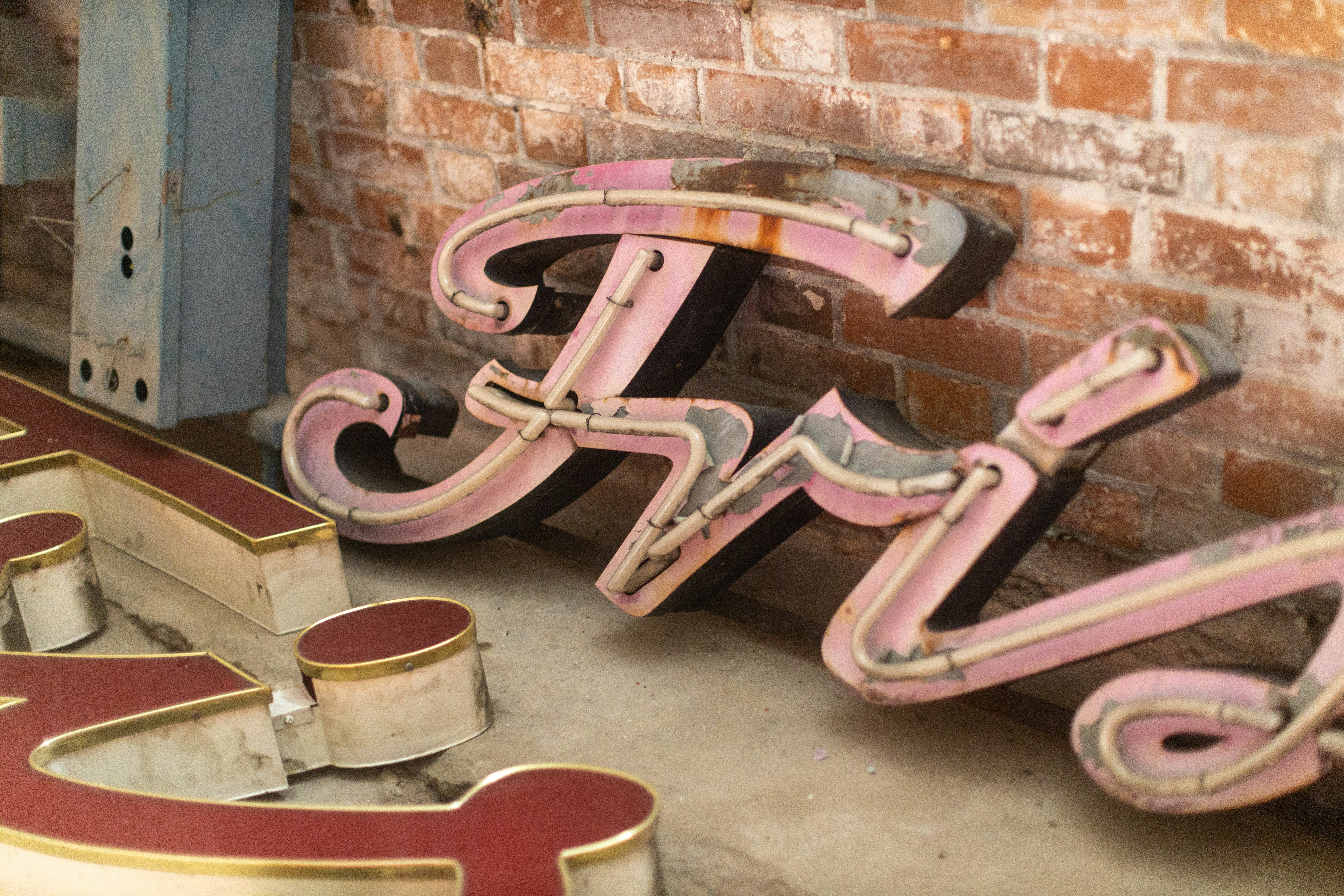 Neon Promise in the Dust: A Pink Sign Resting by Brick