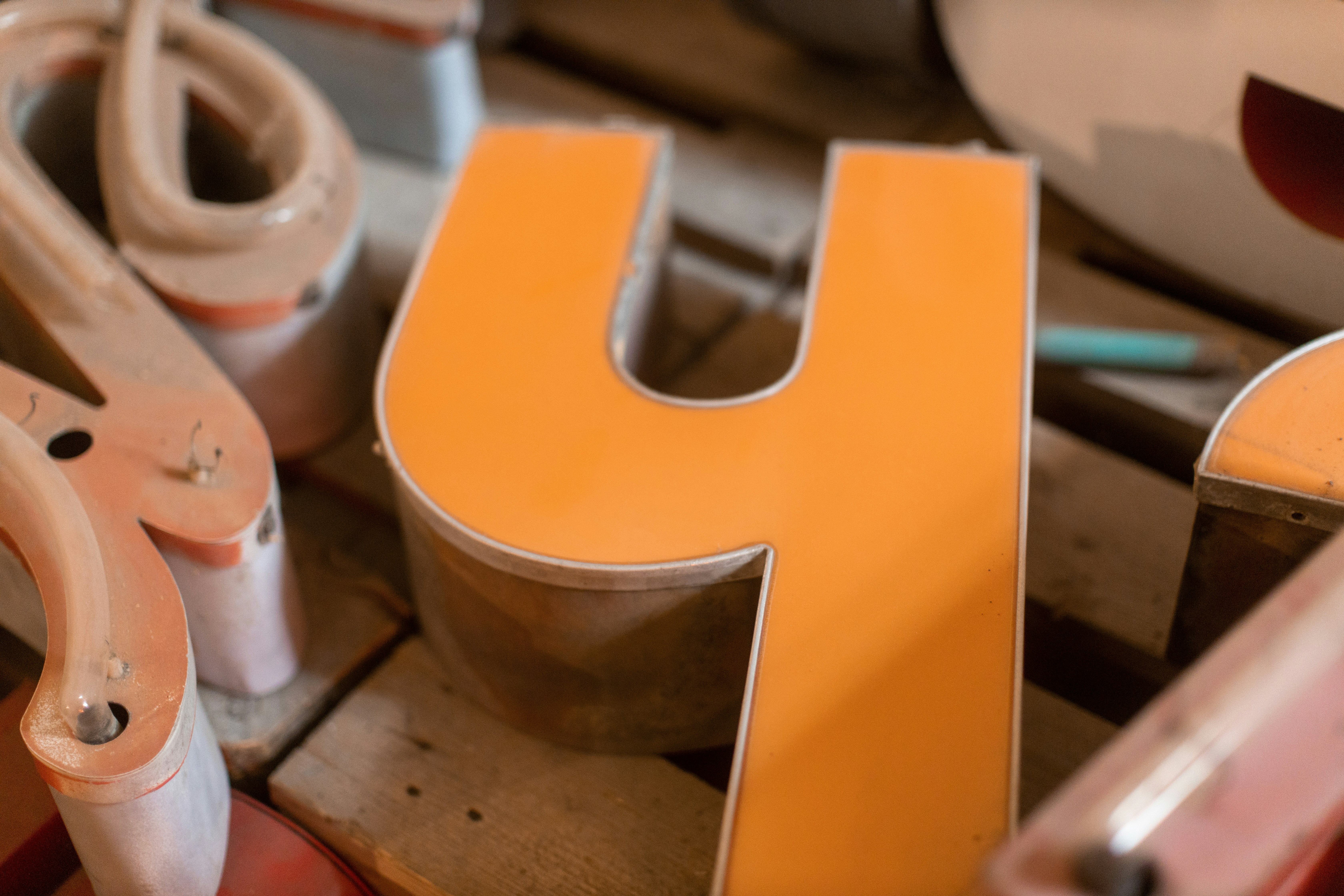 Orange U in the Workshop: A Close-Up of a Sign-Maker's Metal Letter