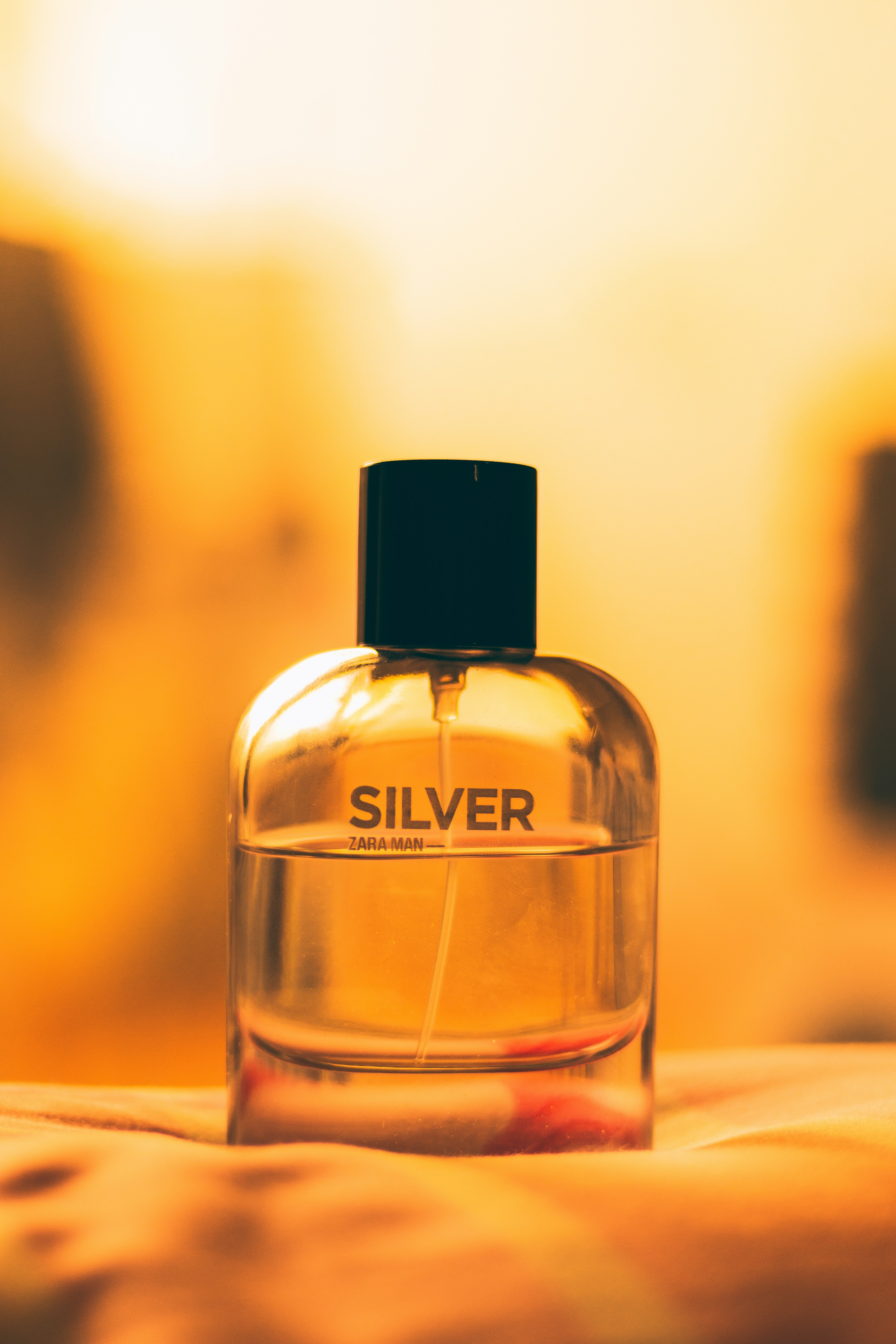 Amber Halo: Minimal Still Life of a Silver Perfume Bottle