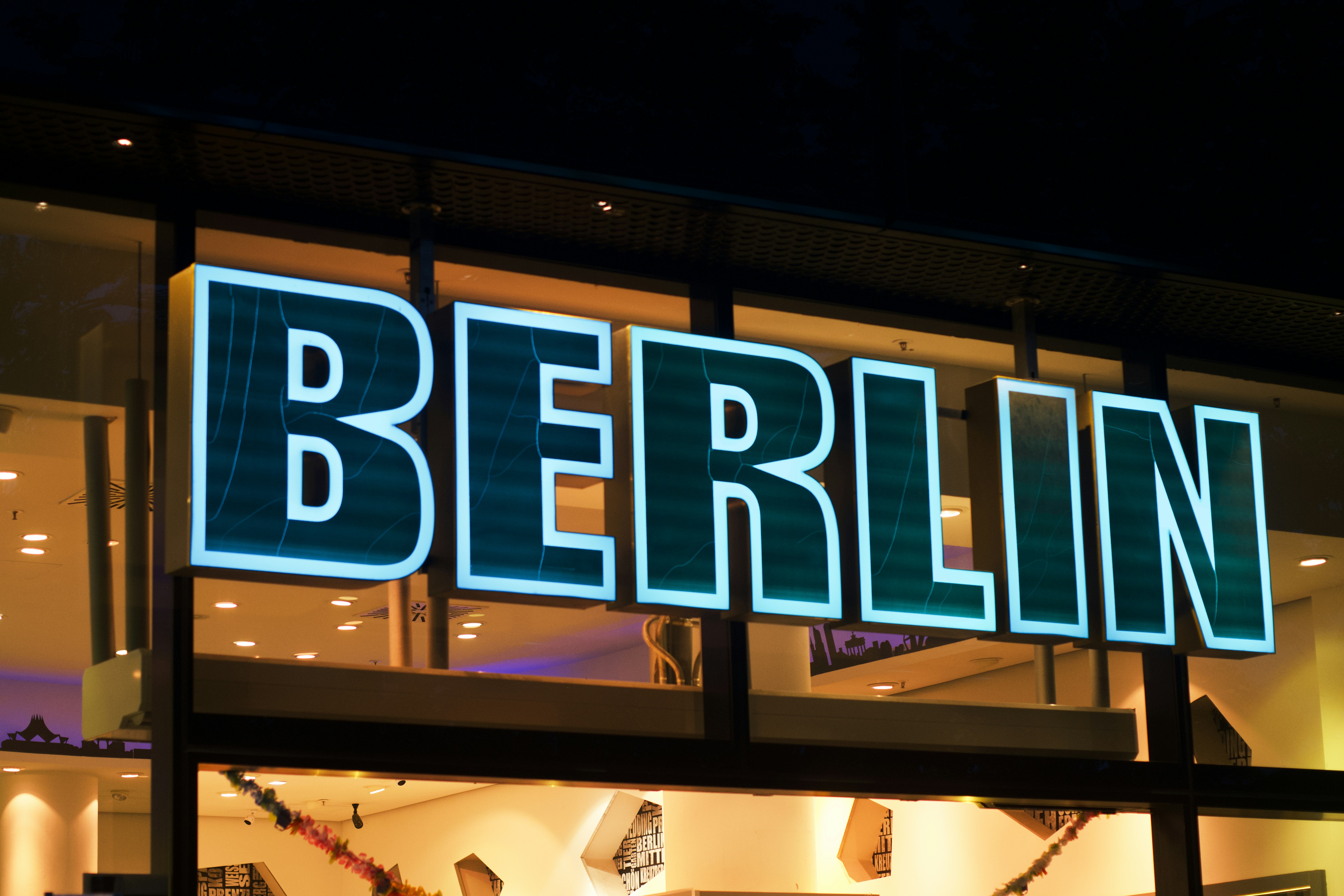 Berlin Neon Blues: Nighttime Shopfront Glow Framed by Glass