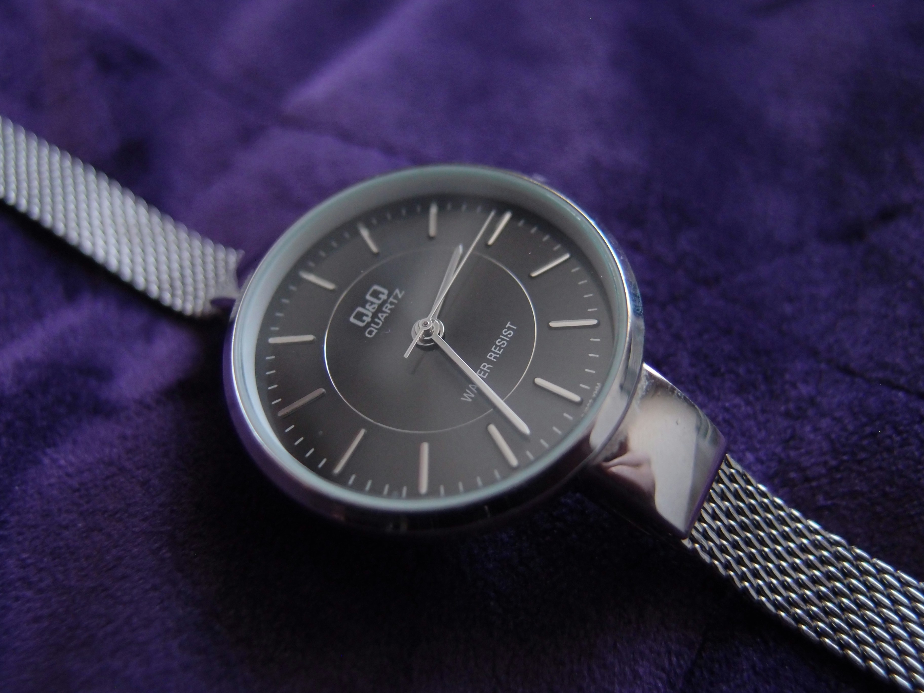 A sleek, modern watch resting on a rich purple velvet surface, showcasing its minimalist design and fine detailing.