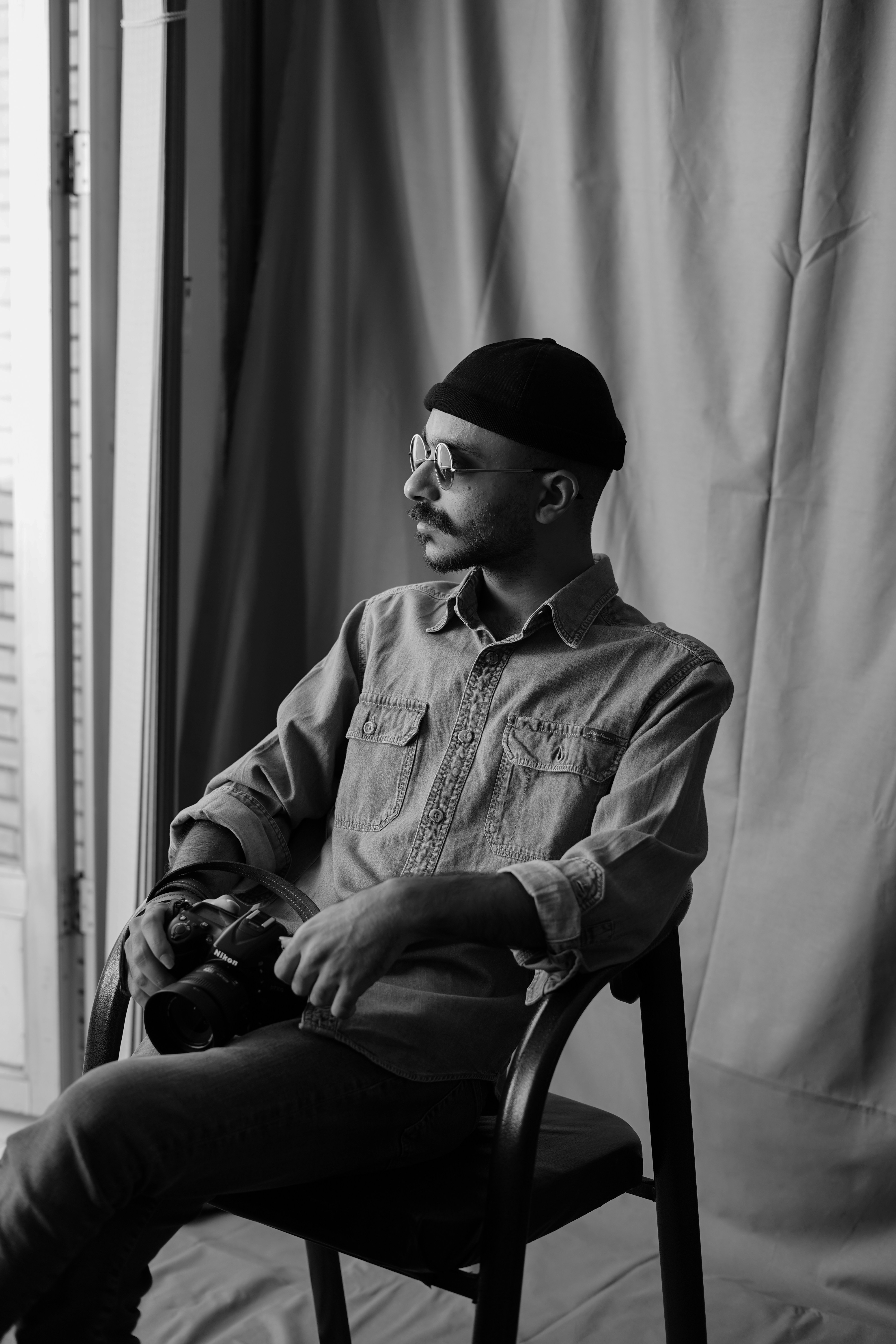 Une personne assise sur une chaise tenant une caméra photo – Photo ...