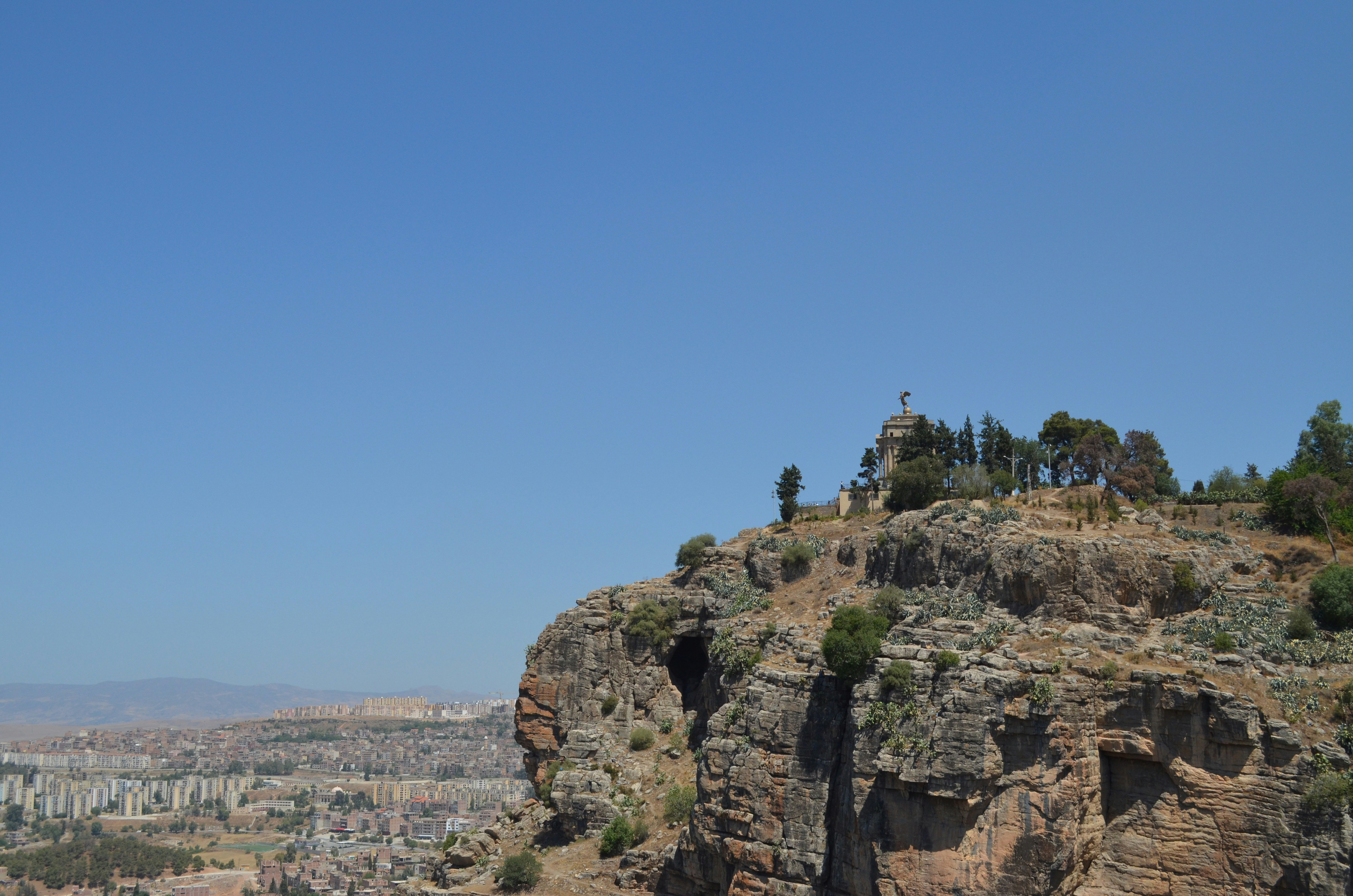Foto Un gran acantilado de roca con una ciudad debajo – Imagen ...