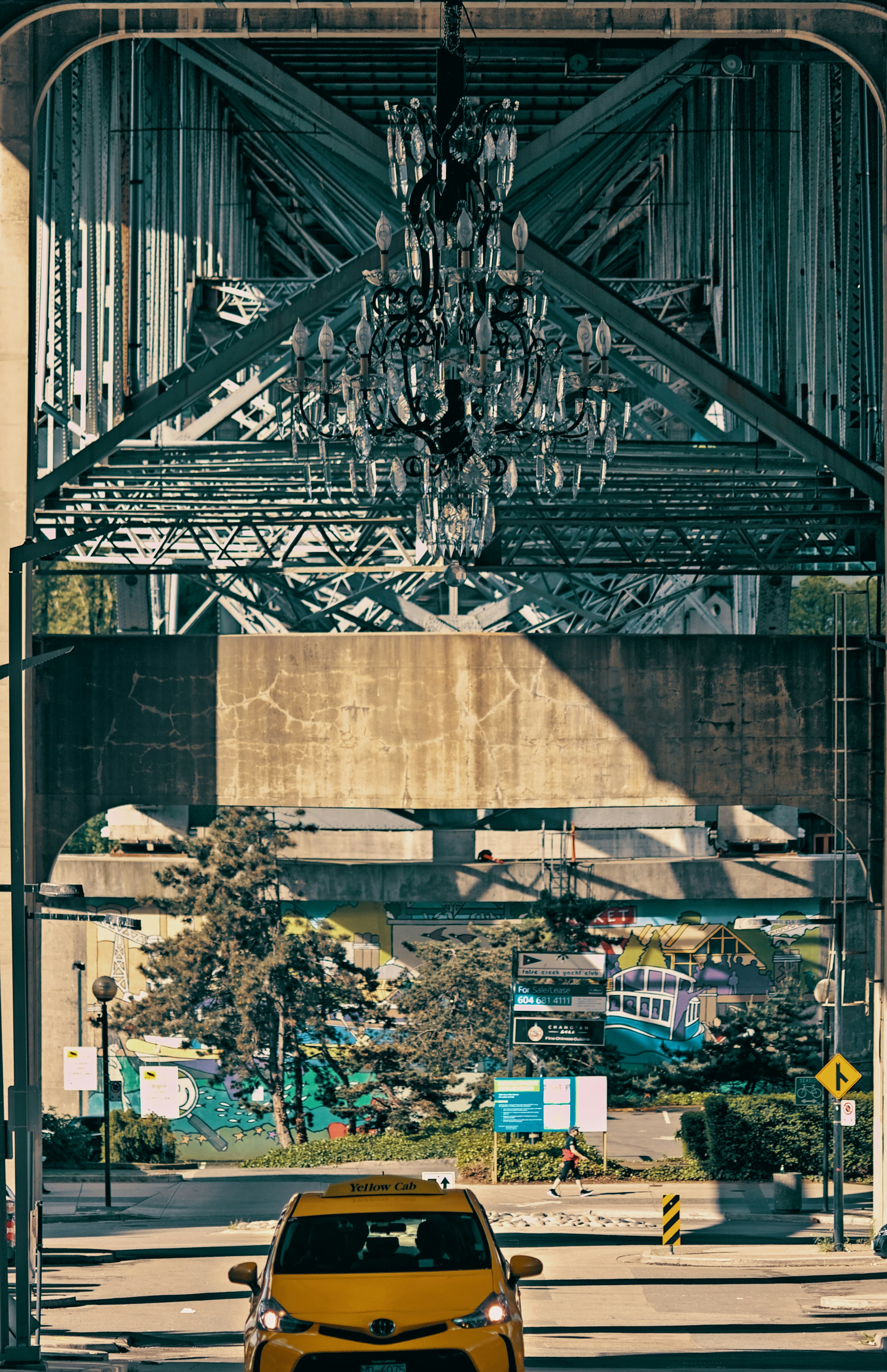 Crystal Under Steel: a chandelier suspended over a sunlit city street