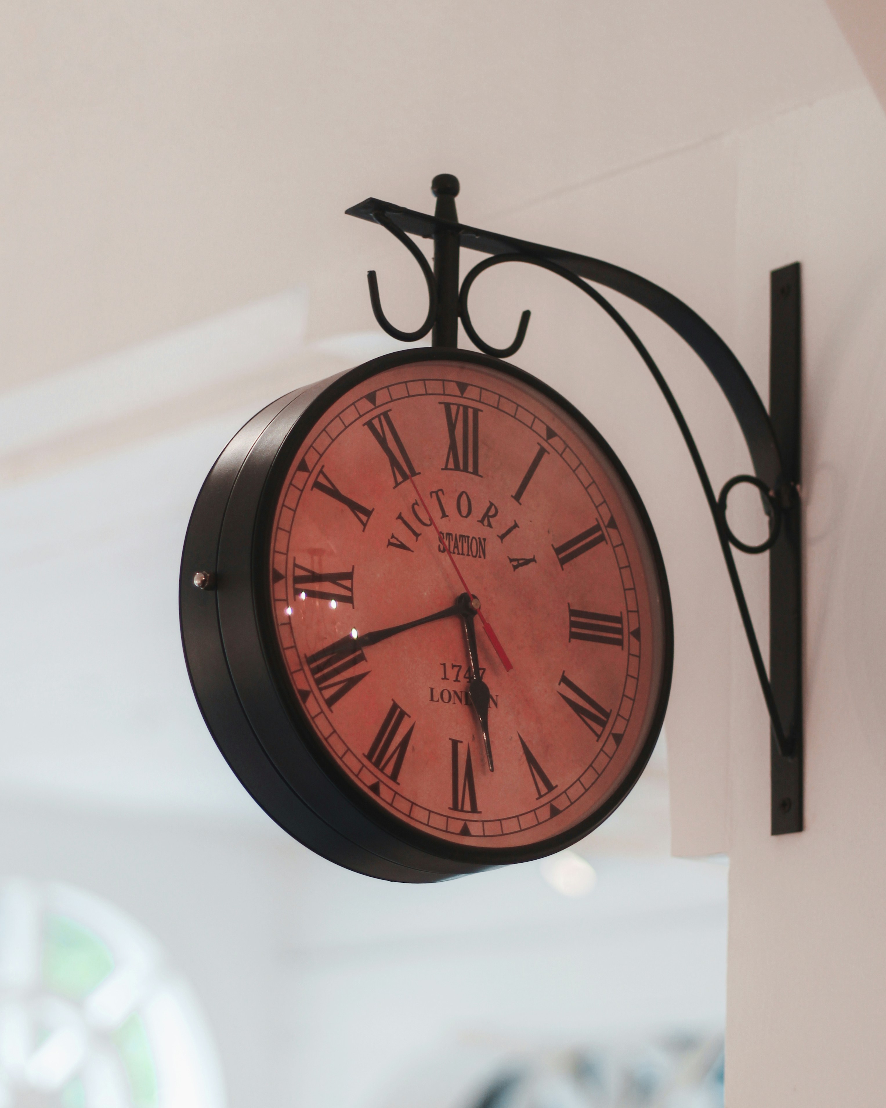 Victorian Red-Face Clock Adorning a Wrought-Iron Bracket