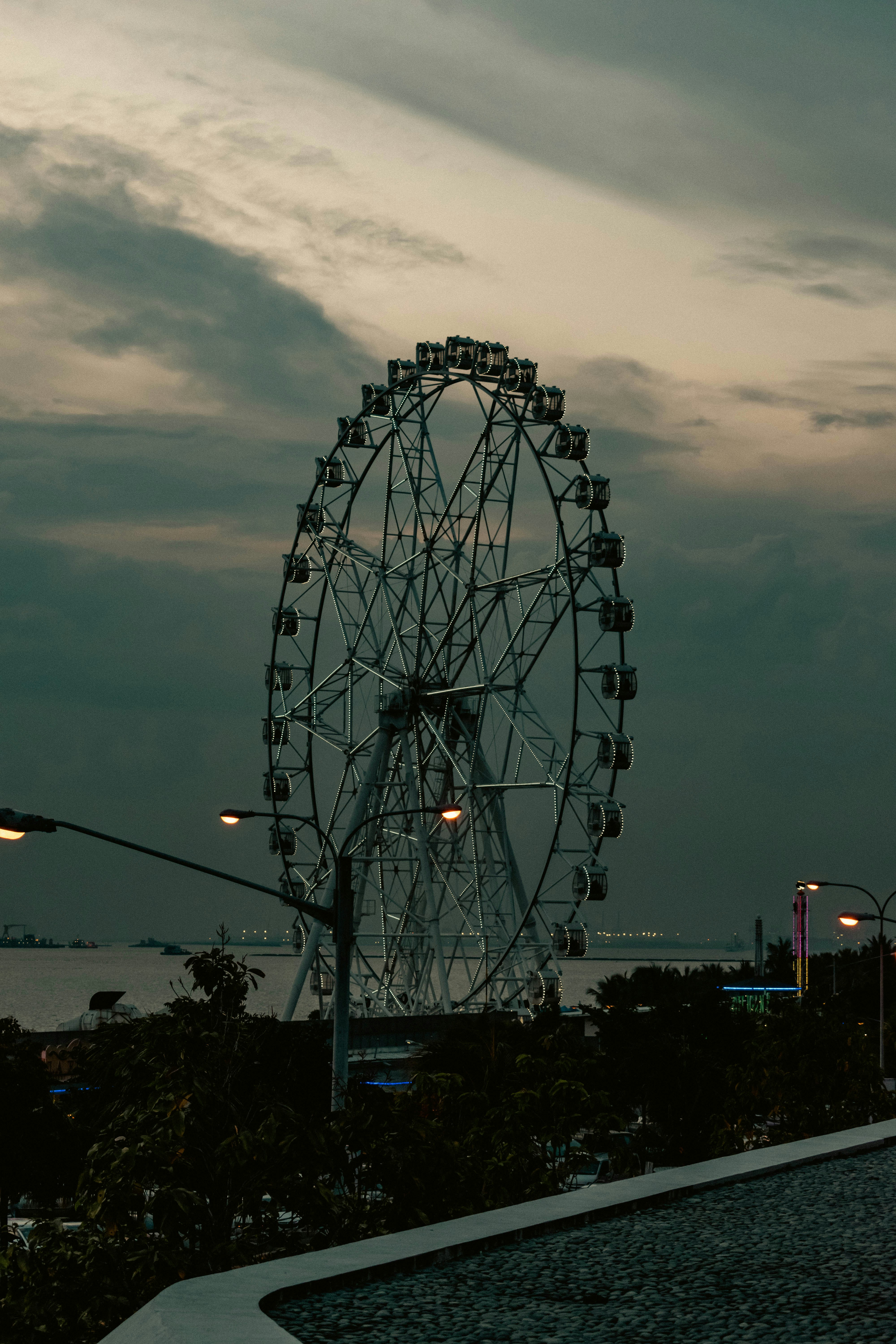 A towering Ferris wheel silhouetted against a moody twilight sky, hinting at the evening's unfolding mysteries.