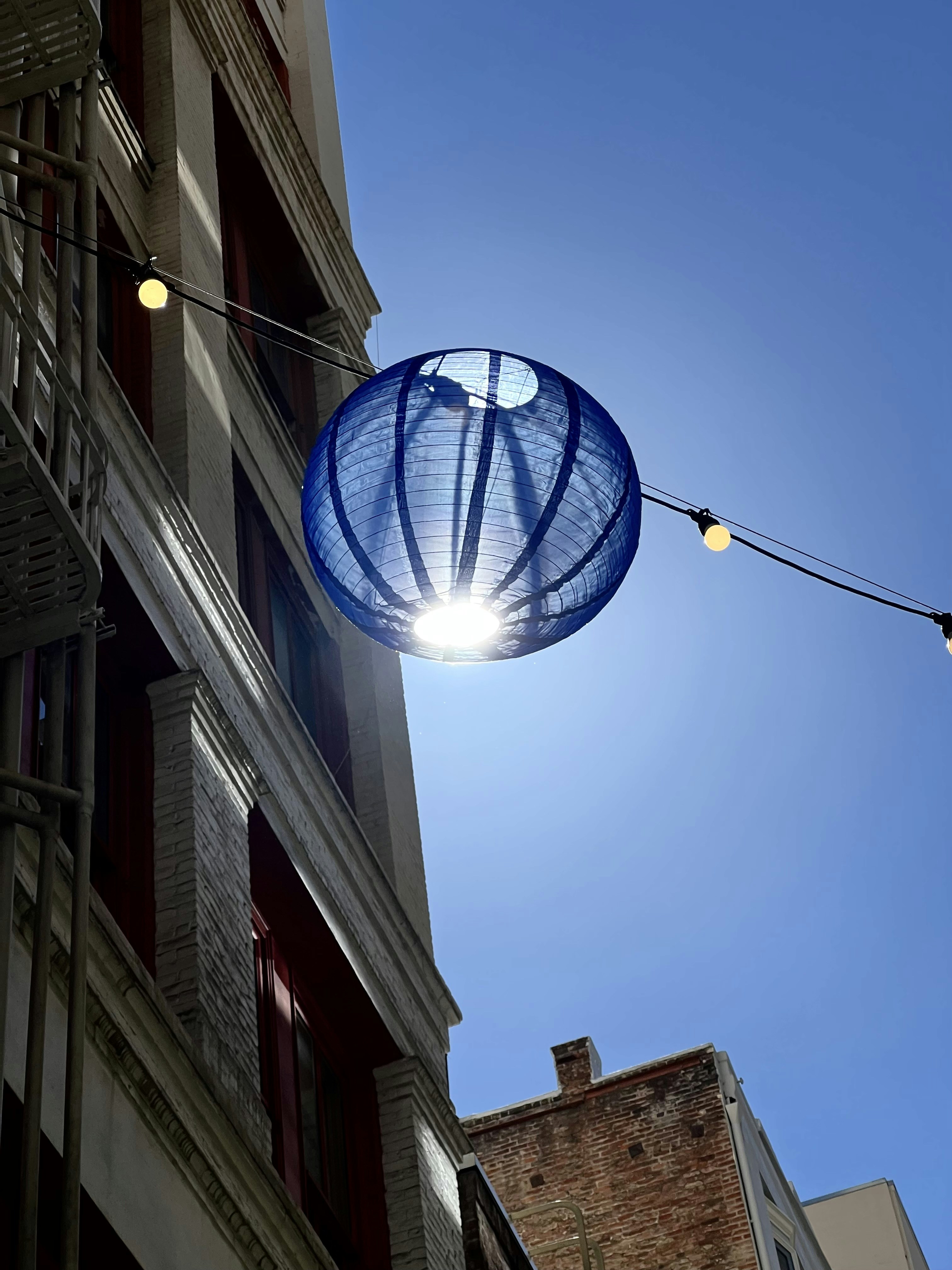 Azure Globe Lantern Glowing in Daylight Above a Historic Urban Facade