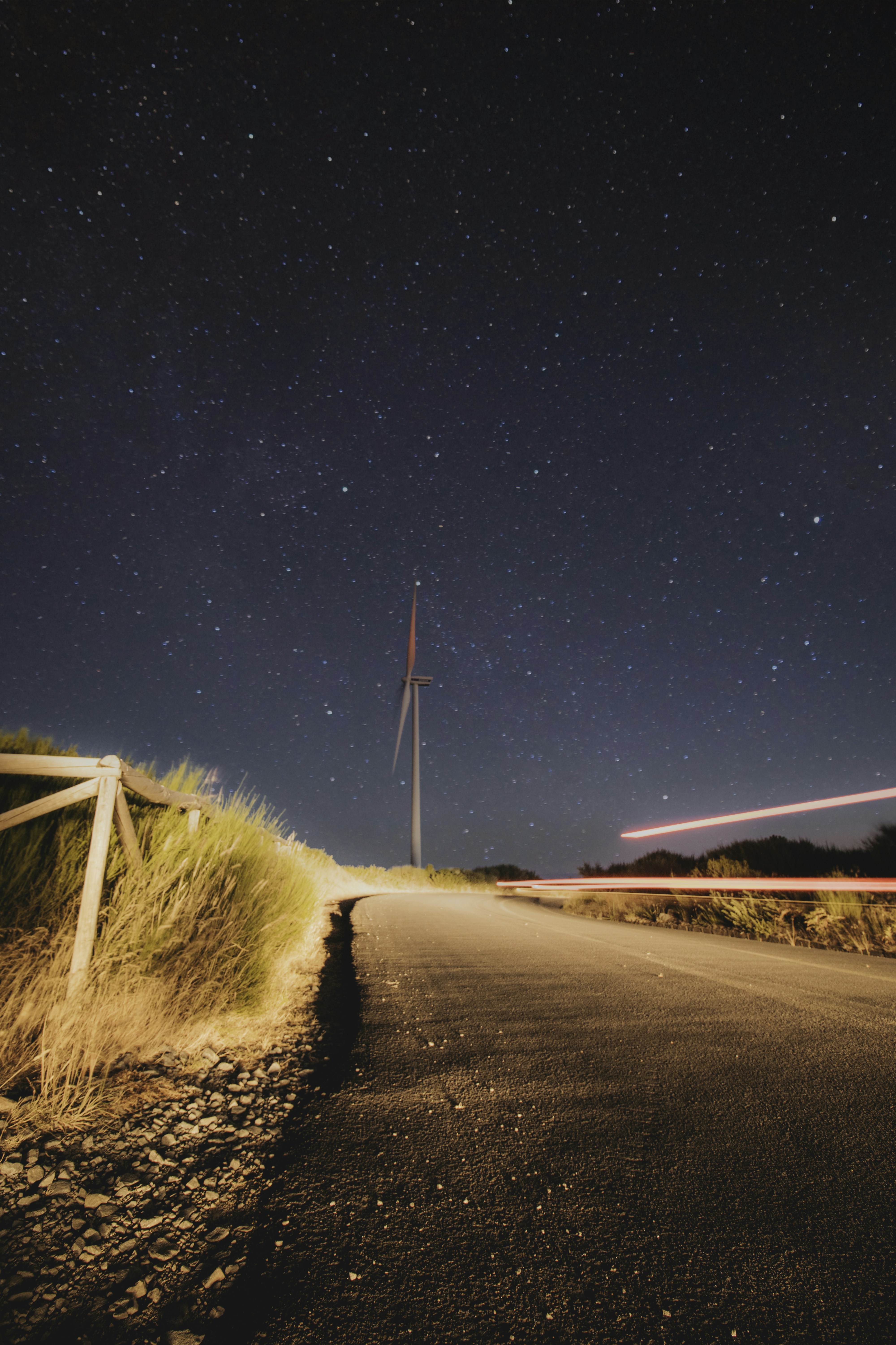Trail Under a Starlit Sky with a Wind Turbine Silhouette