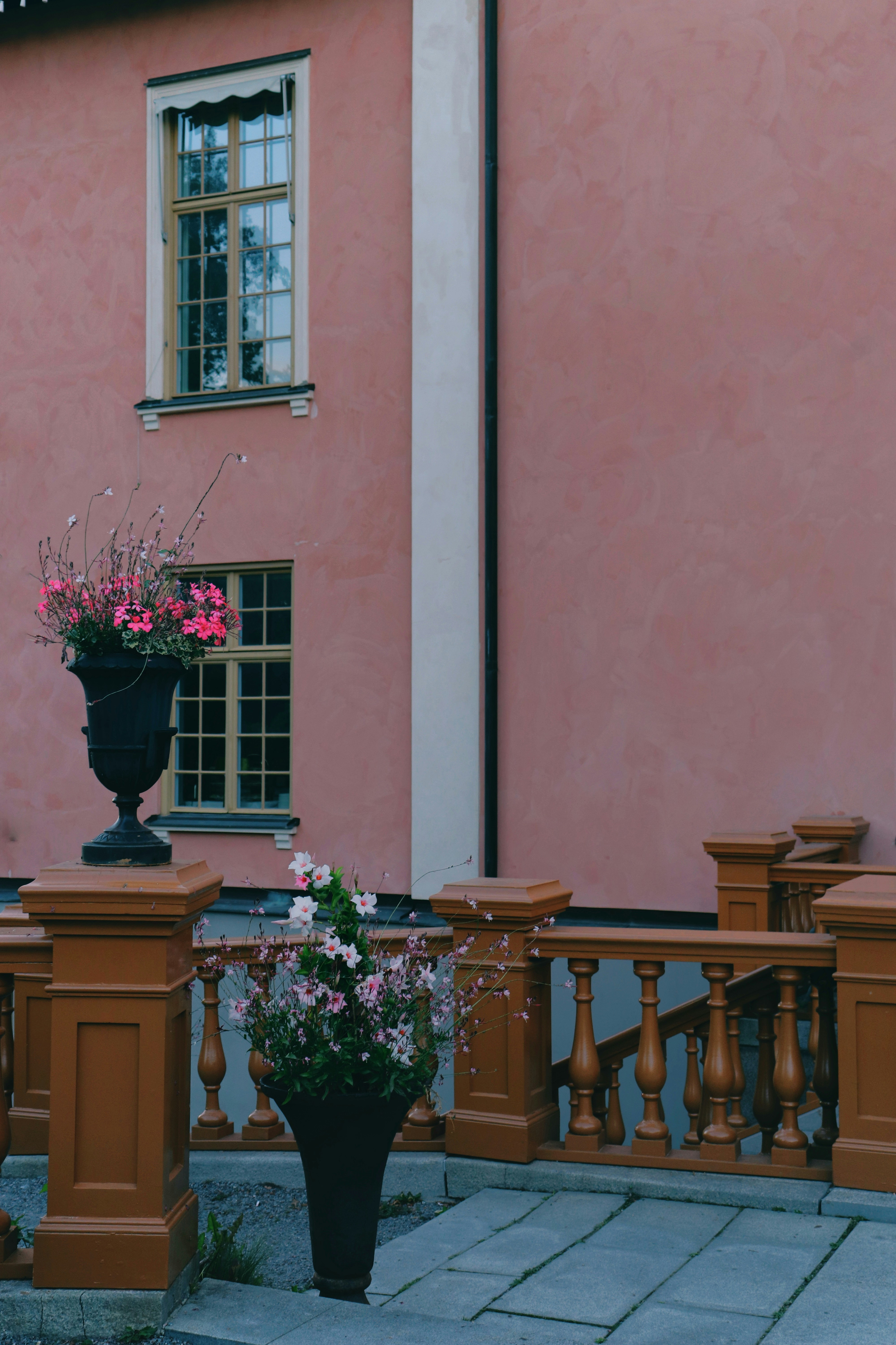 Blush Facade Bloom: Pink Flowers Framing a Courtyard Urn