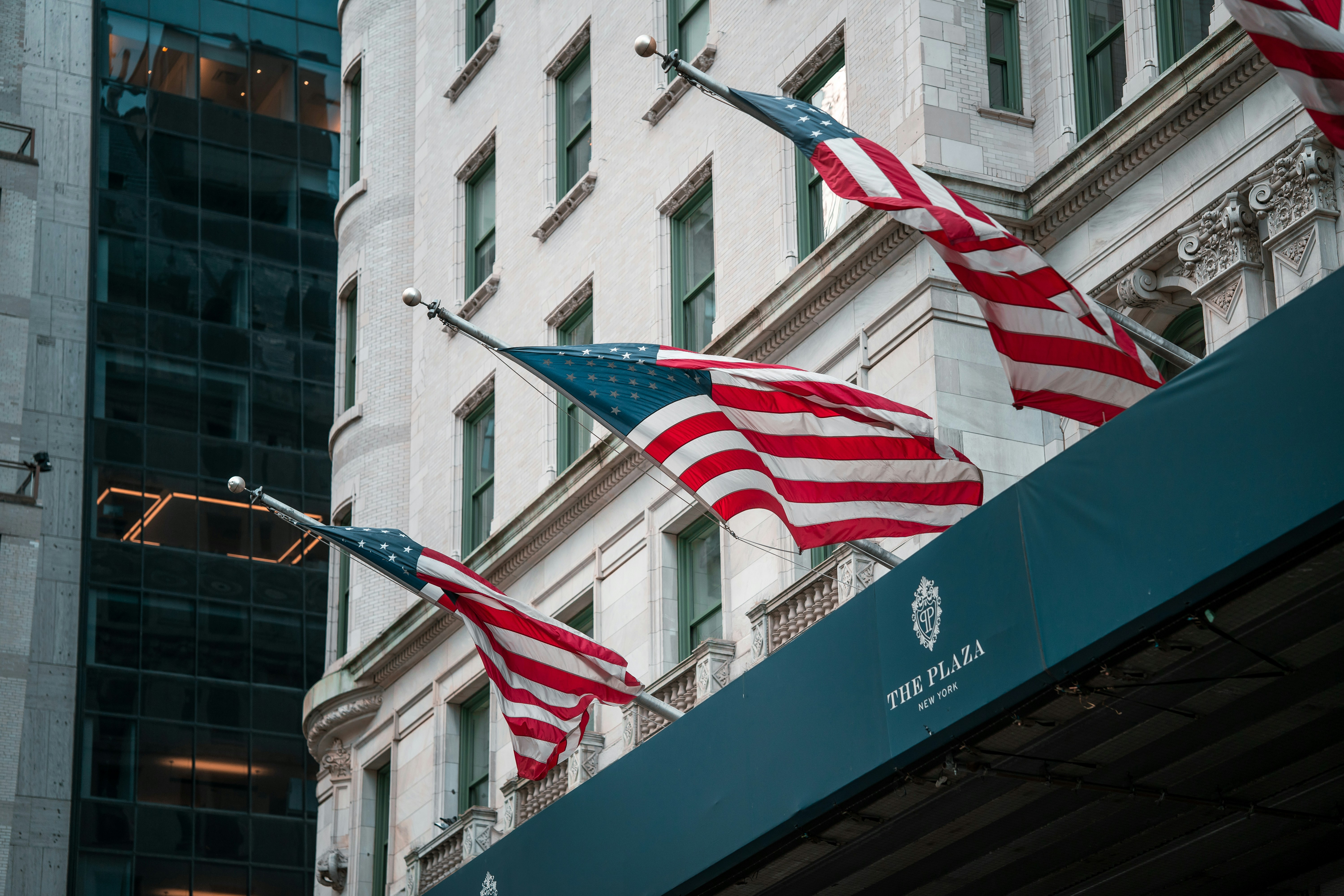 A group of flags flying in front of a building photo – Free Flag Image ...