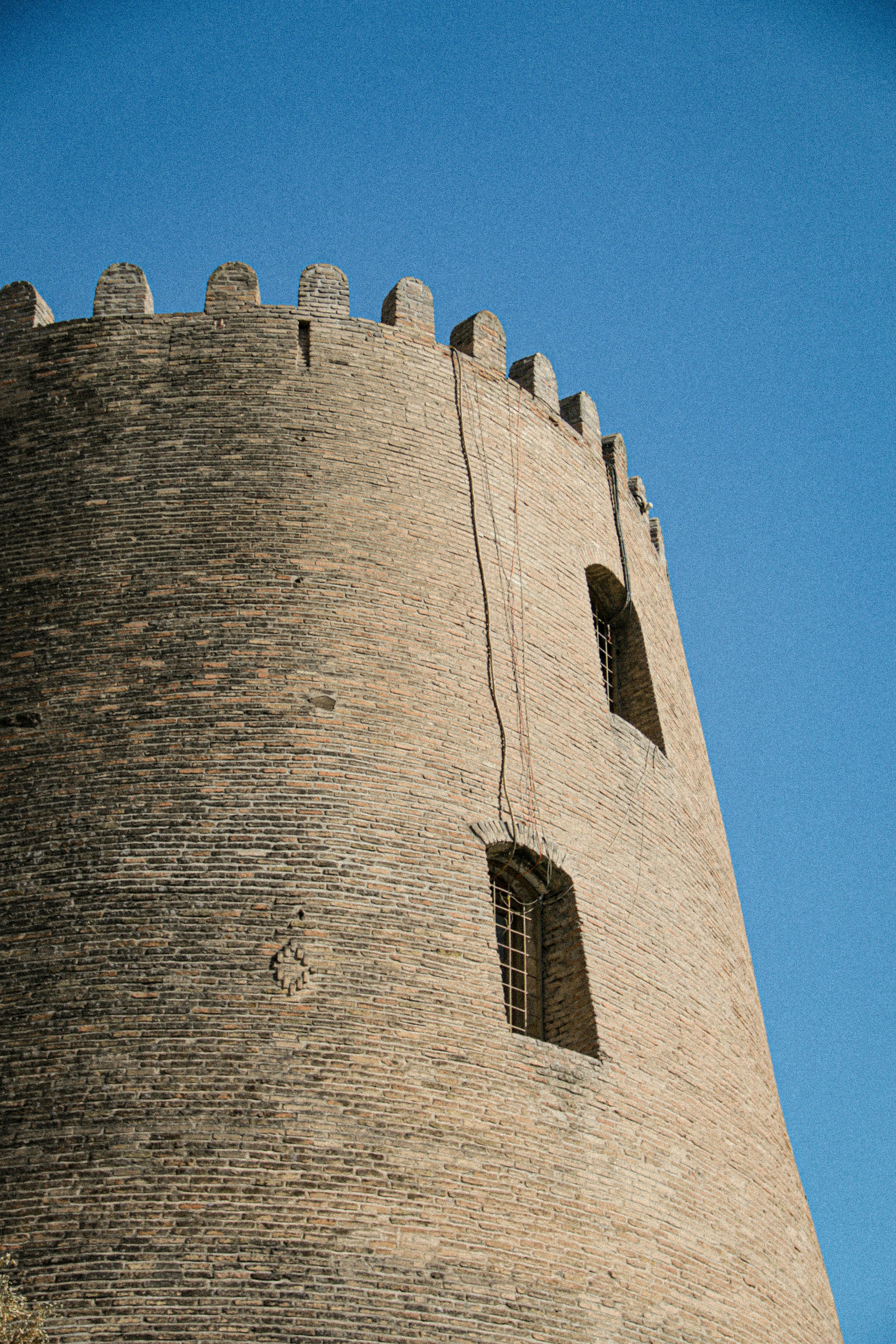 Ancient brick tower rises against a clear blue sky, showcasing architectural details and historical significance.