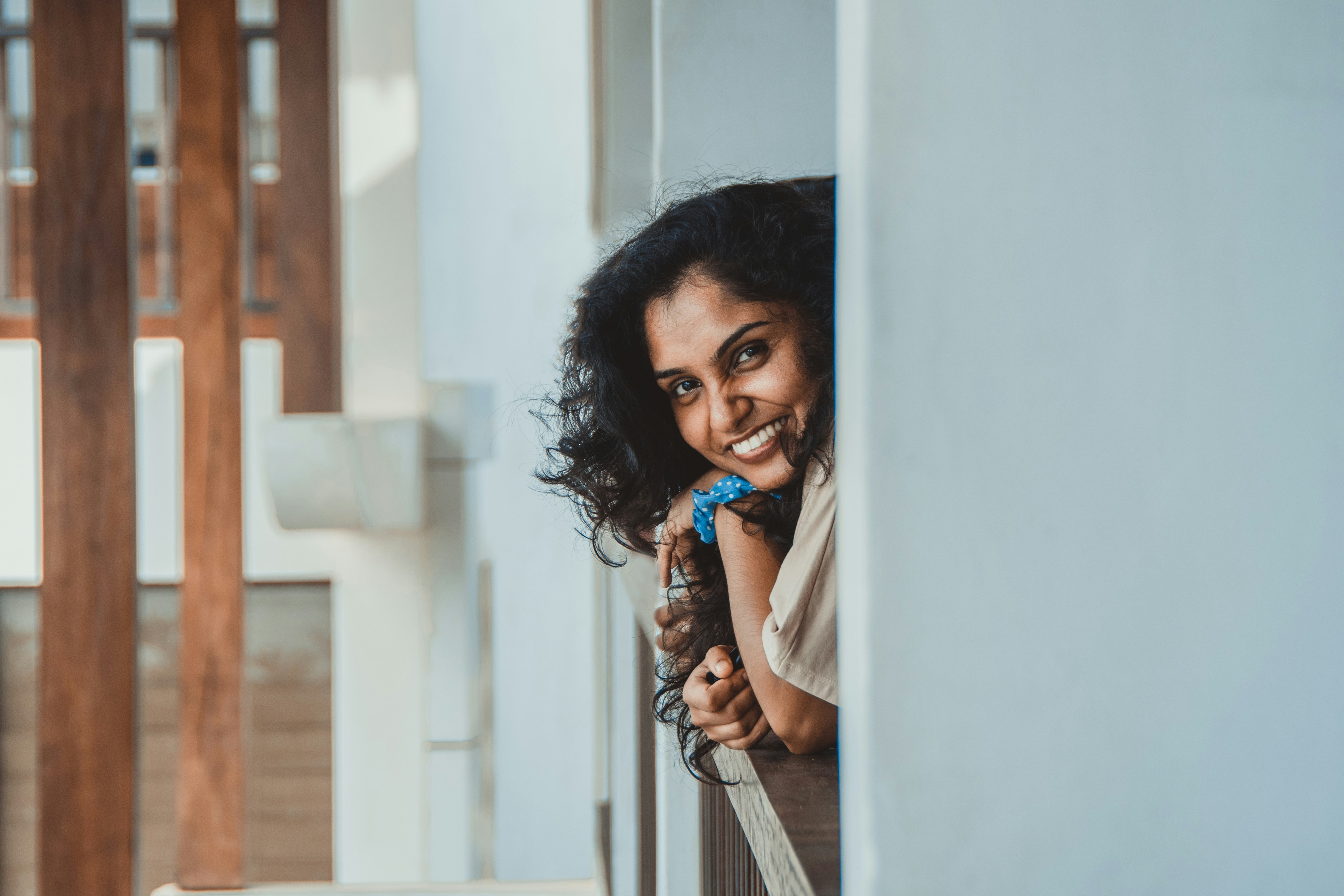 Curious Balcony Smile: A Light-Soaked Moment Peering from the Blue Wall