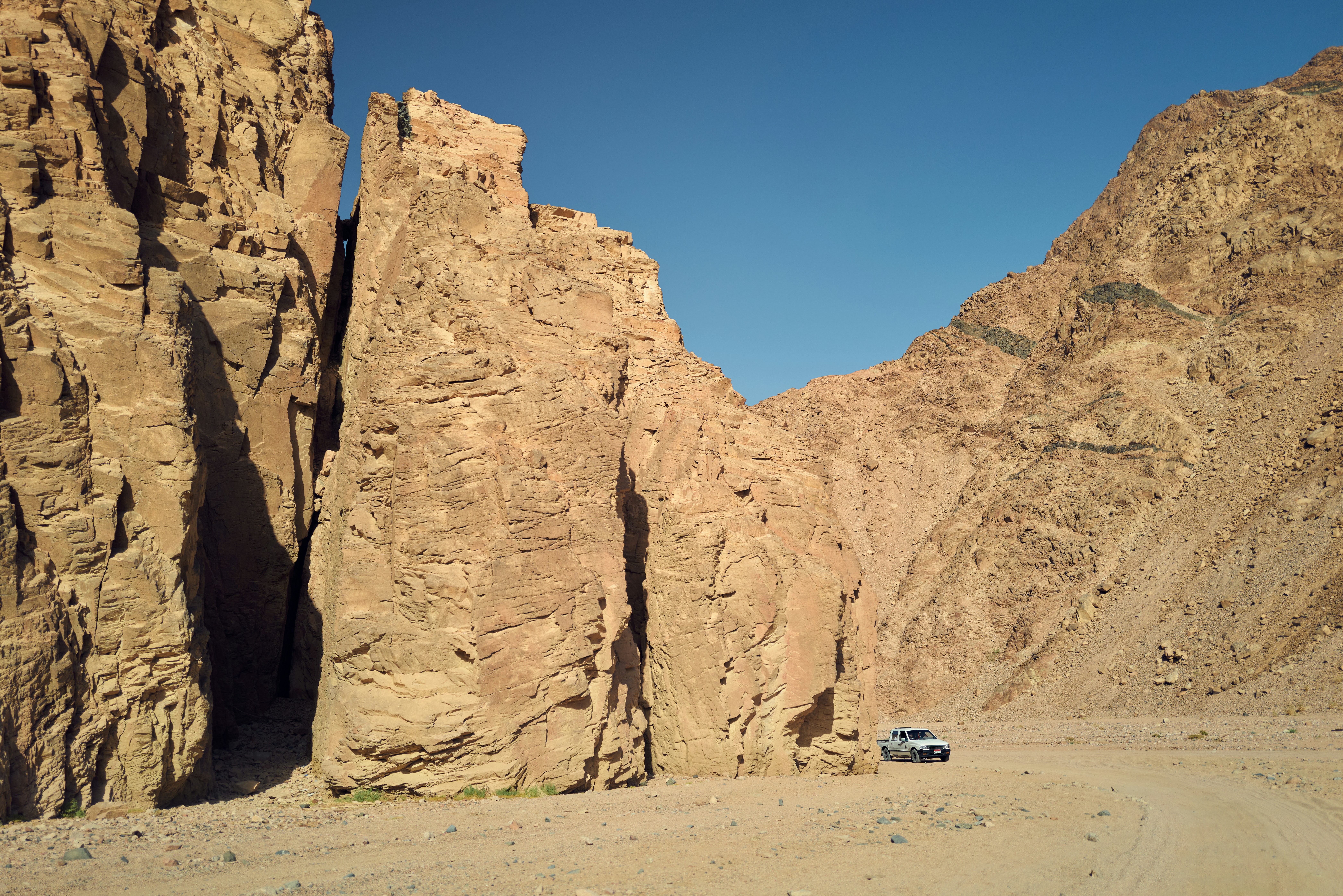 A car driving on a dirt road between large rocky cliffs photo – Free ...