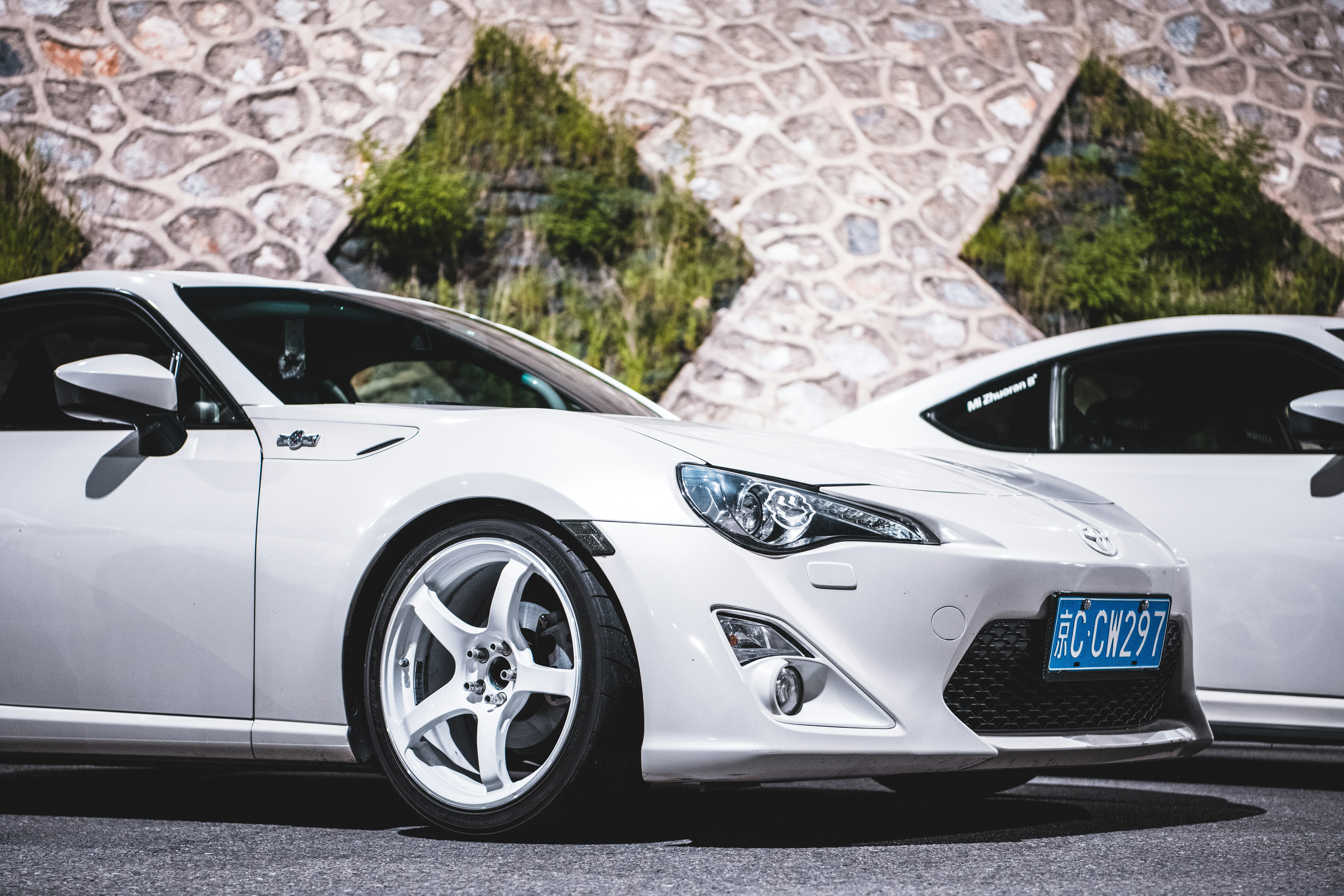 Pristine White Coupé Under a Stone-Wall Backdrop
