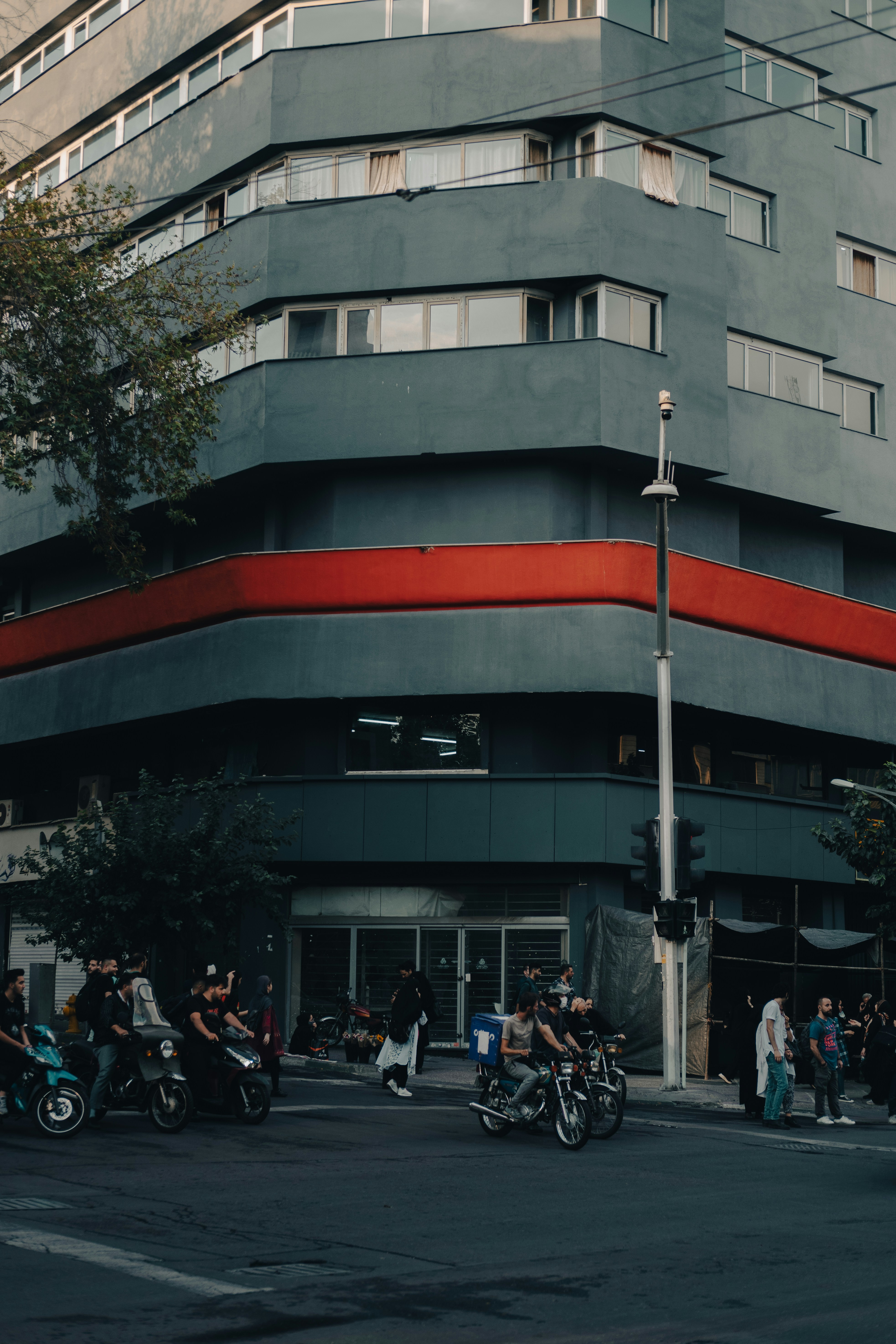 Red Curve Over Teal Facade: Street Life at the Corner