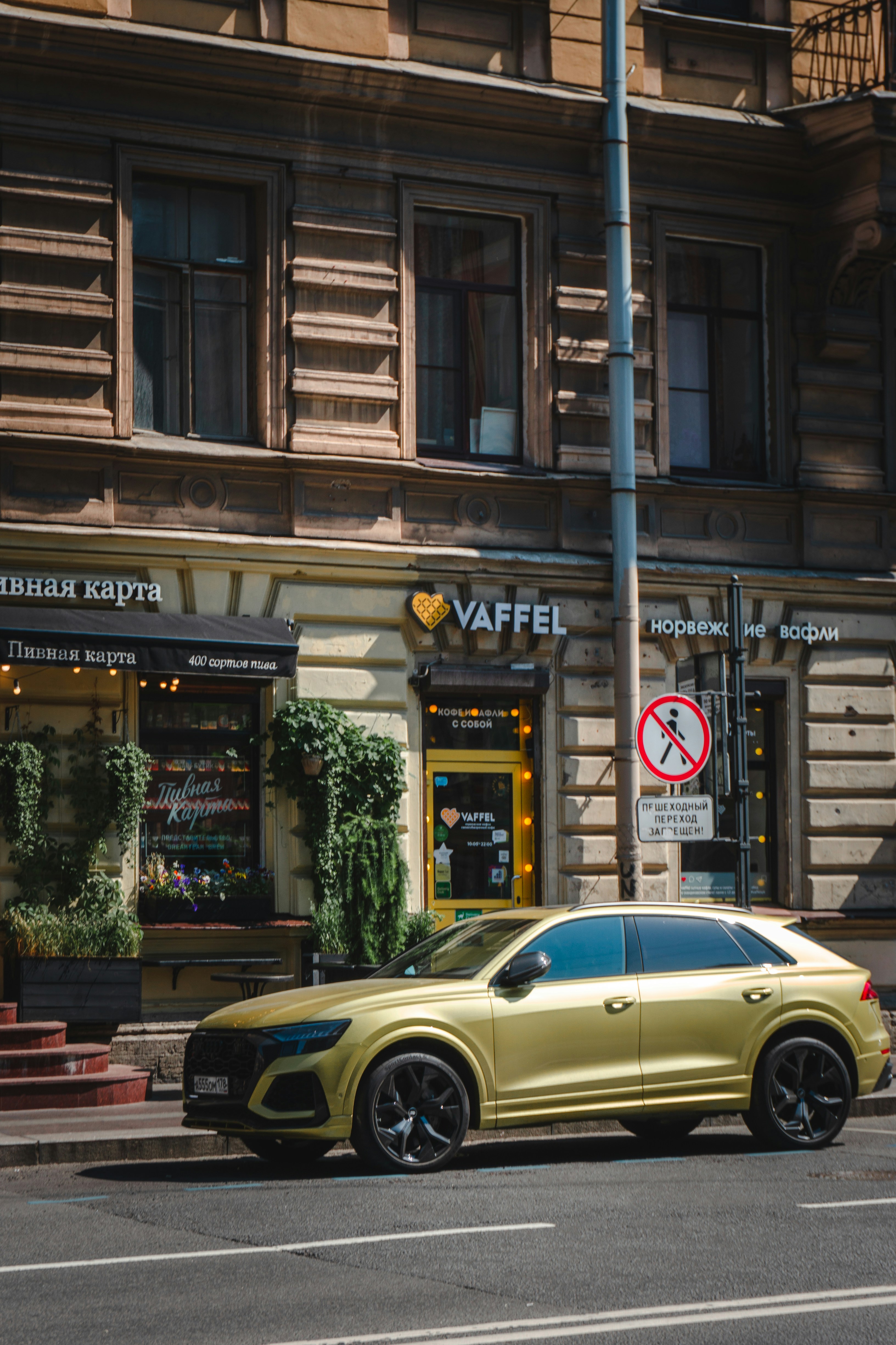 Golden SUV at a sunlit brick-and-stone city storefront