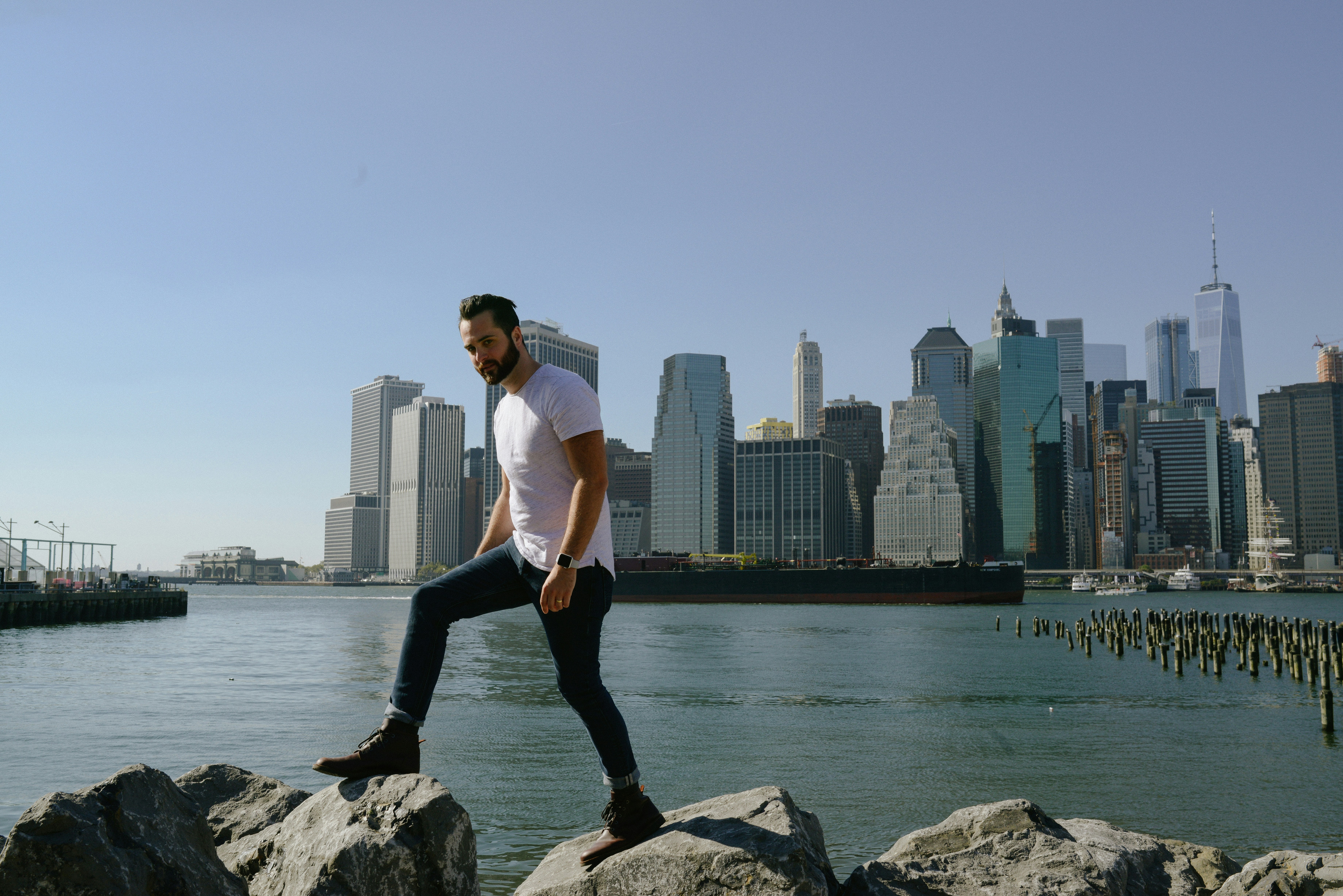 Harbor Step: A lone figure balances on rugged rocks with a skyline backdrop