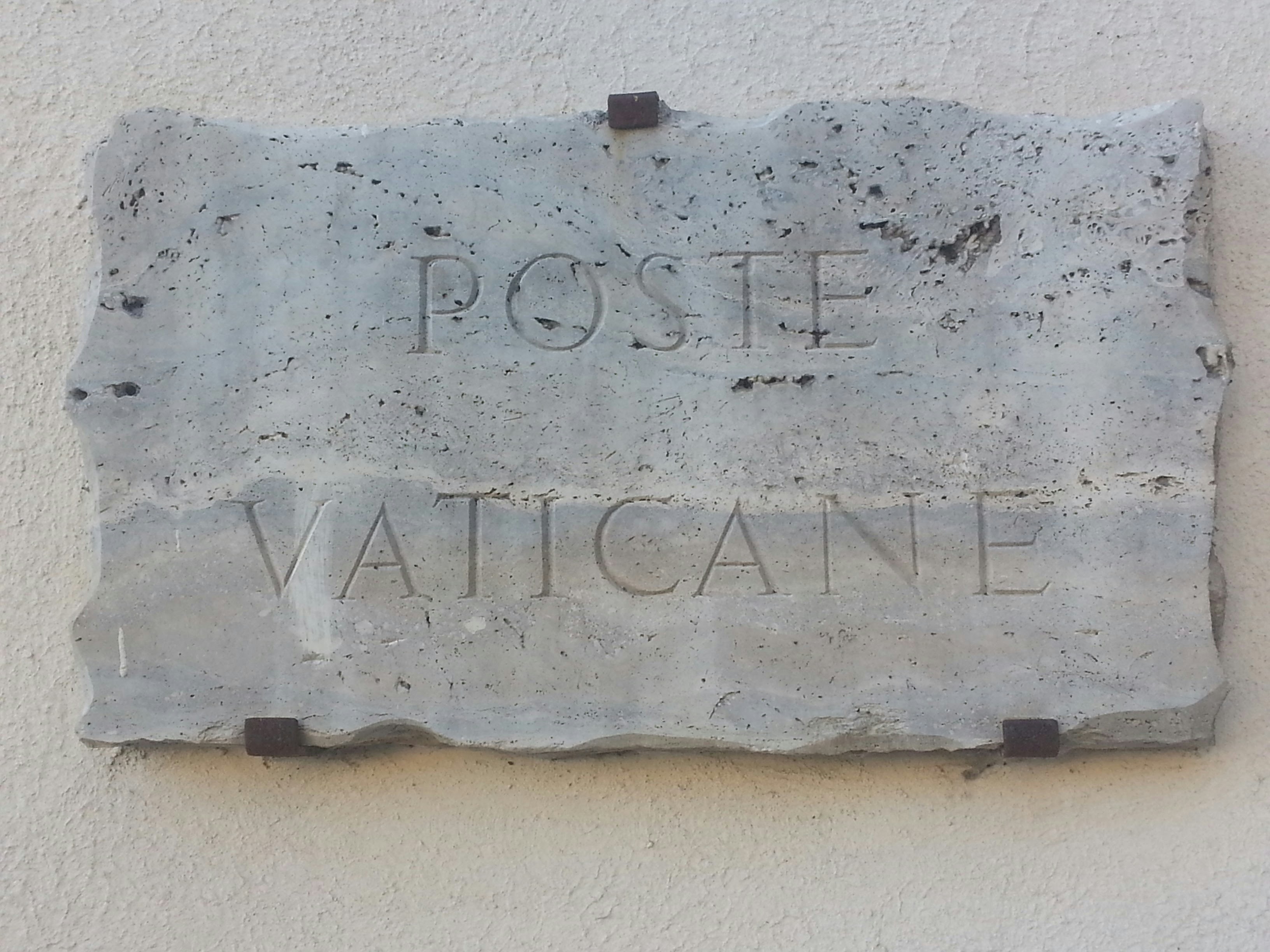 Weathered stone plaque displaying the words 'POSTE VATICANE,' indicating the postal services of the Vatican. The texture and craftsmanship reflect the historical significance of the location.