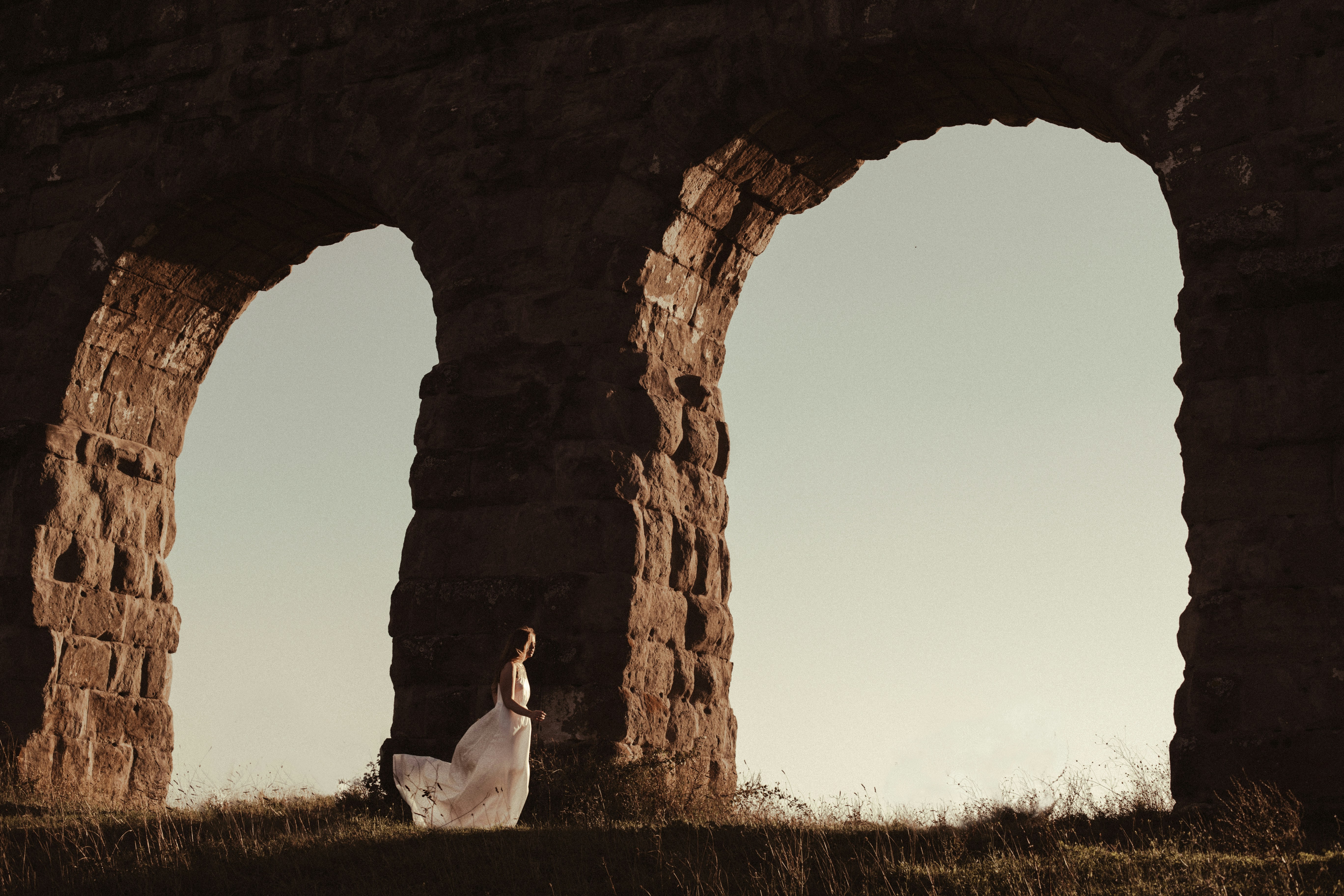 Ruins and Bride: A Lone Figure at Dawn Beside Ancient Arches