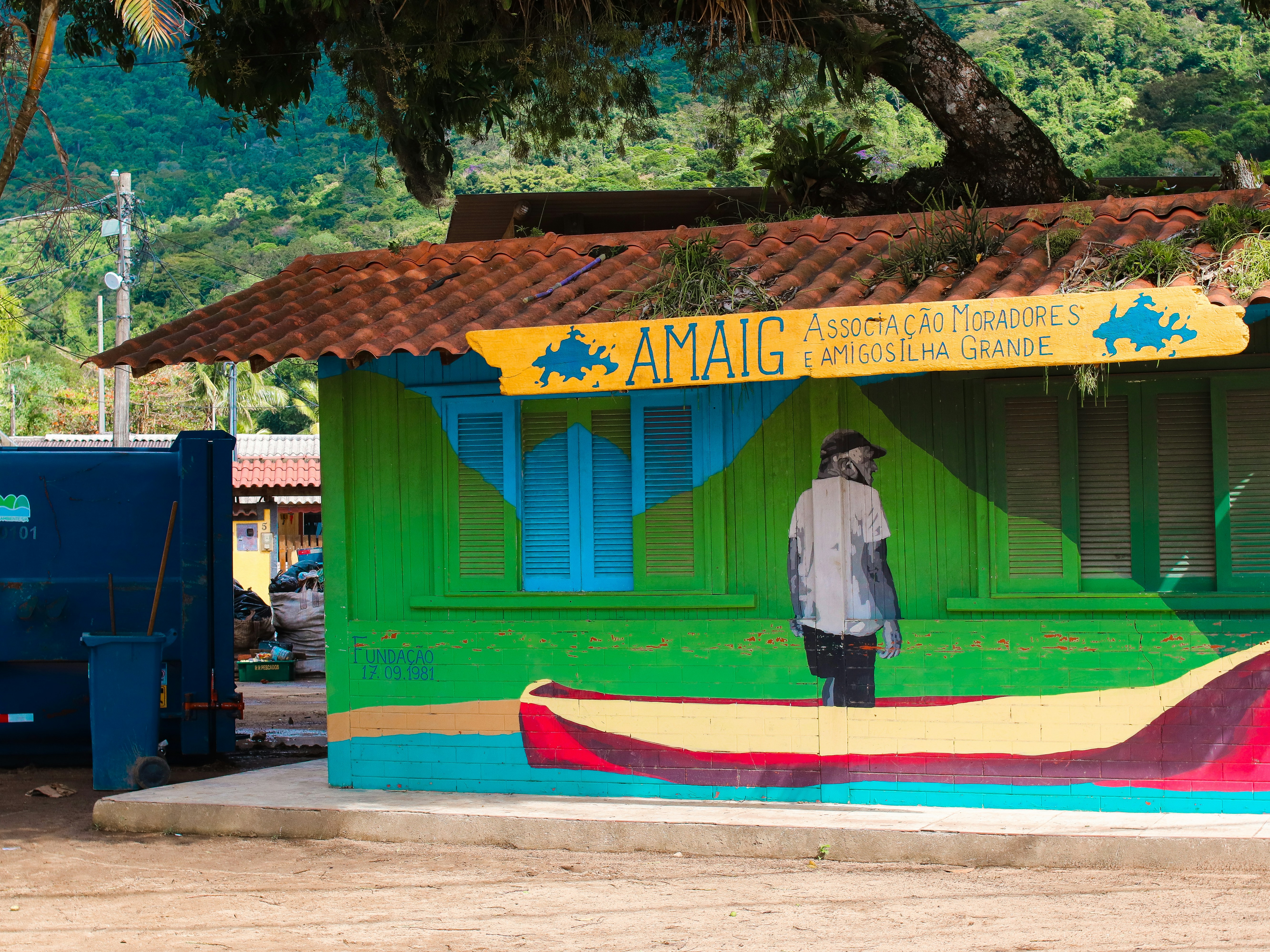 Person standing in front of a colorful market stall with vibrant mural and red roof.