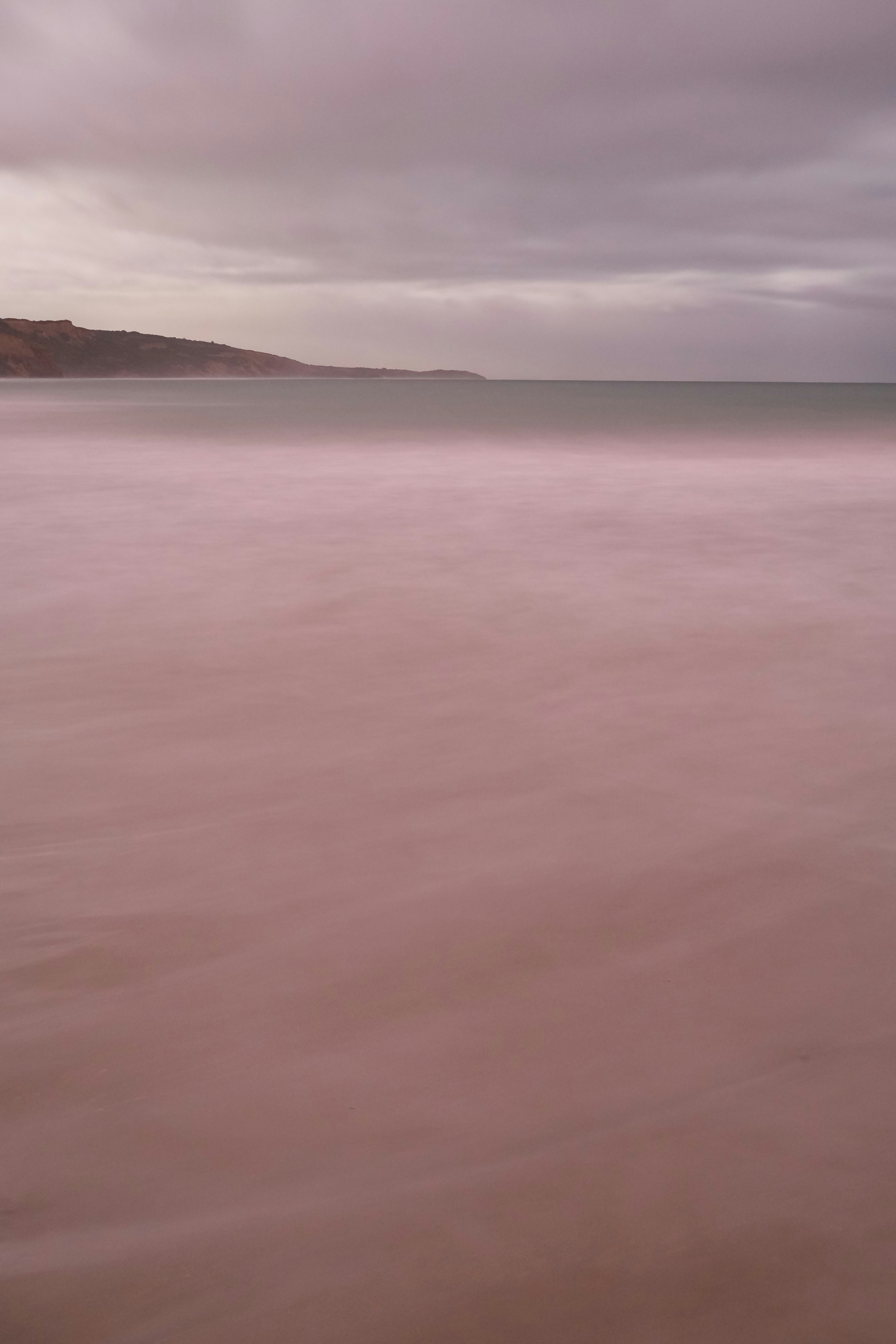 Just after sunset the sea and clouds are still a soft pink. The long exposure blurs the incoming tide